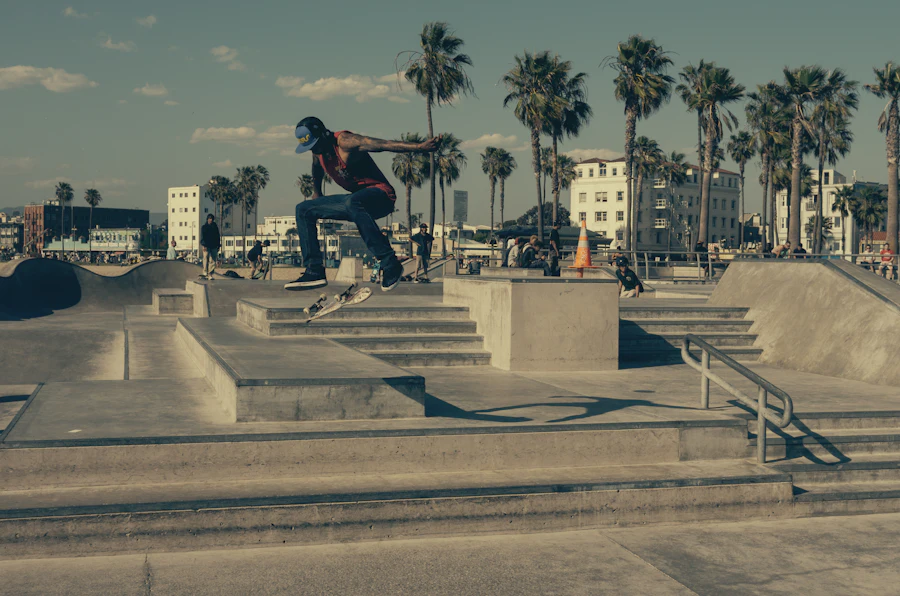 Skateboarder performing a trick in a sunlit skate park surrounded by palm trees and urban architecture.