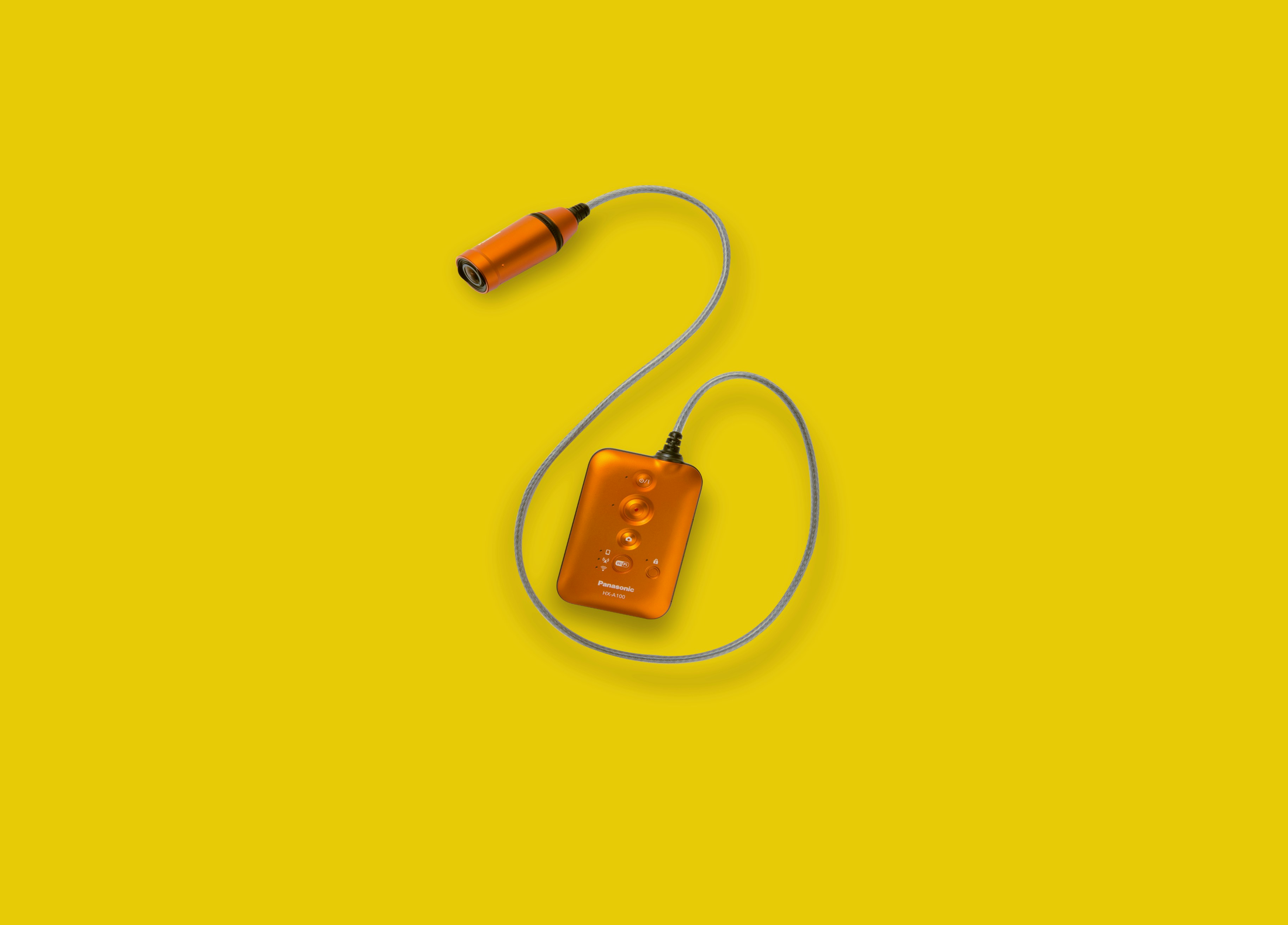 Product photograph featuring an orange electronic connector with a coiled gray cable on a solid yellow background.