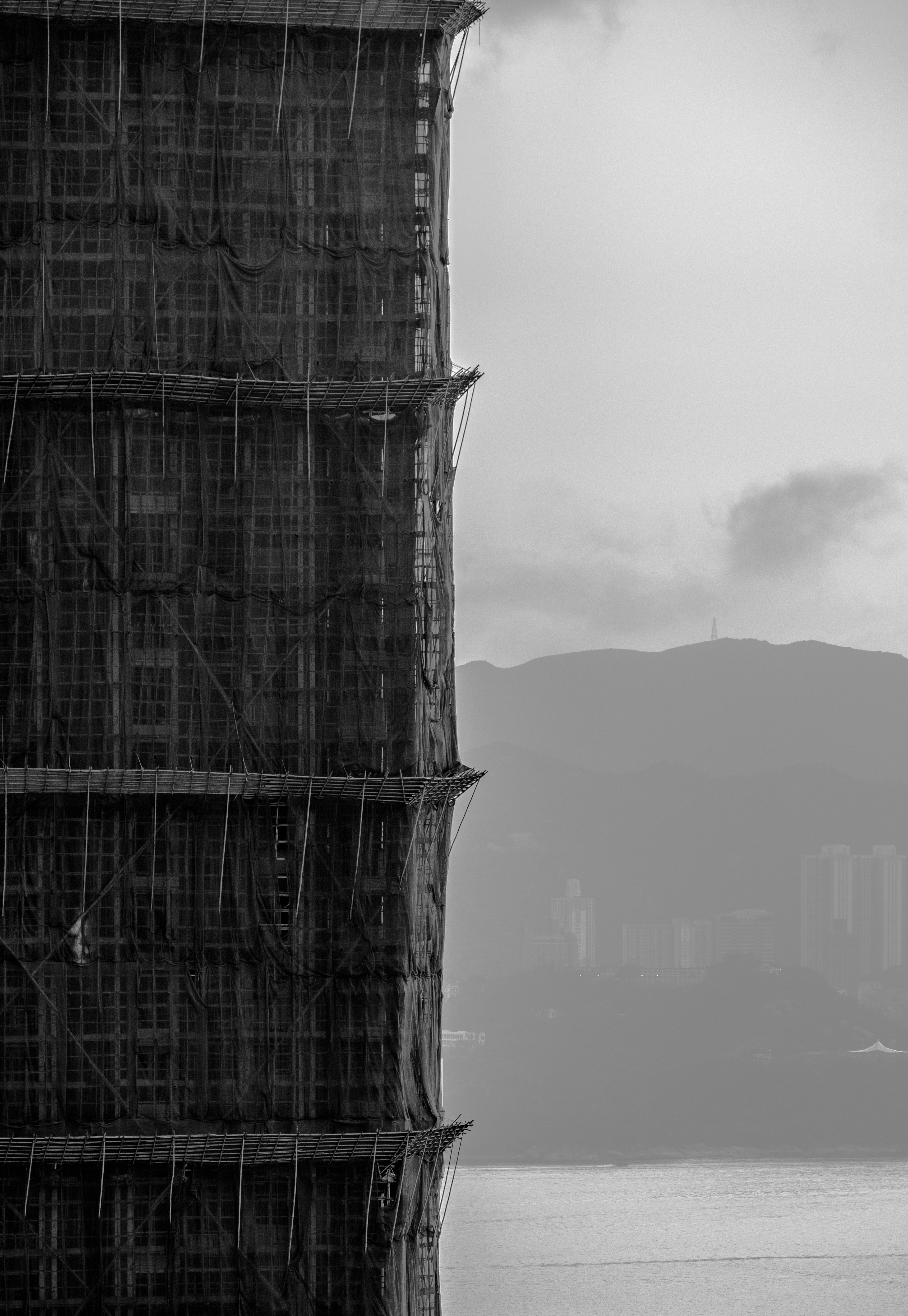 Monochrome Monolith: Scaffolded Tower Framing the Distant Harbor