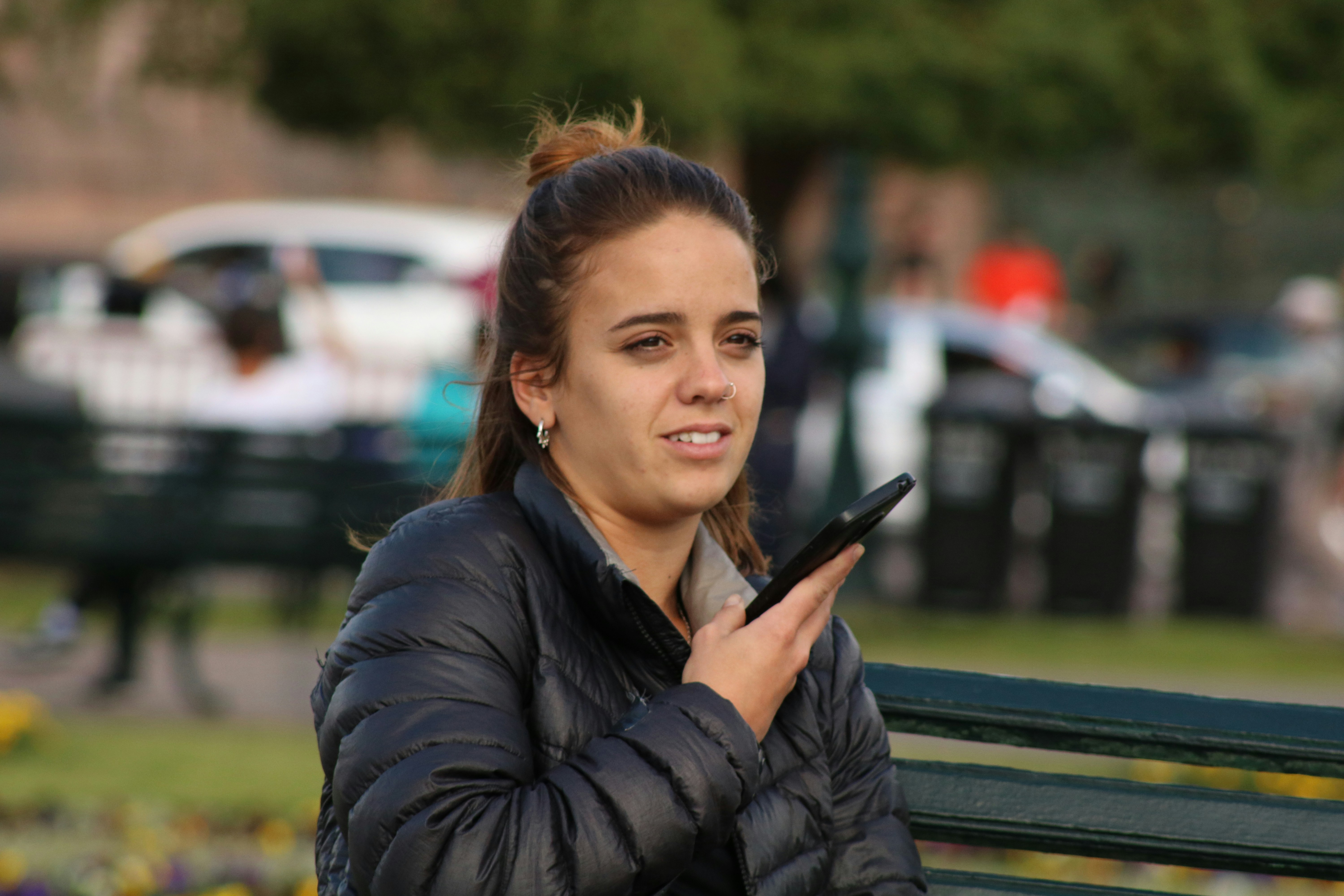 Parkside Pause: A Woman with a Phone in Soft-Blurred Urban Park