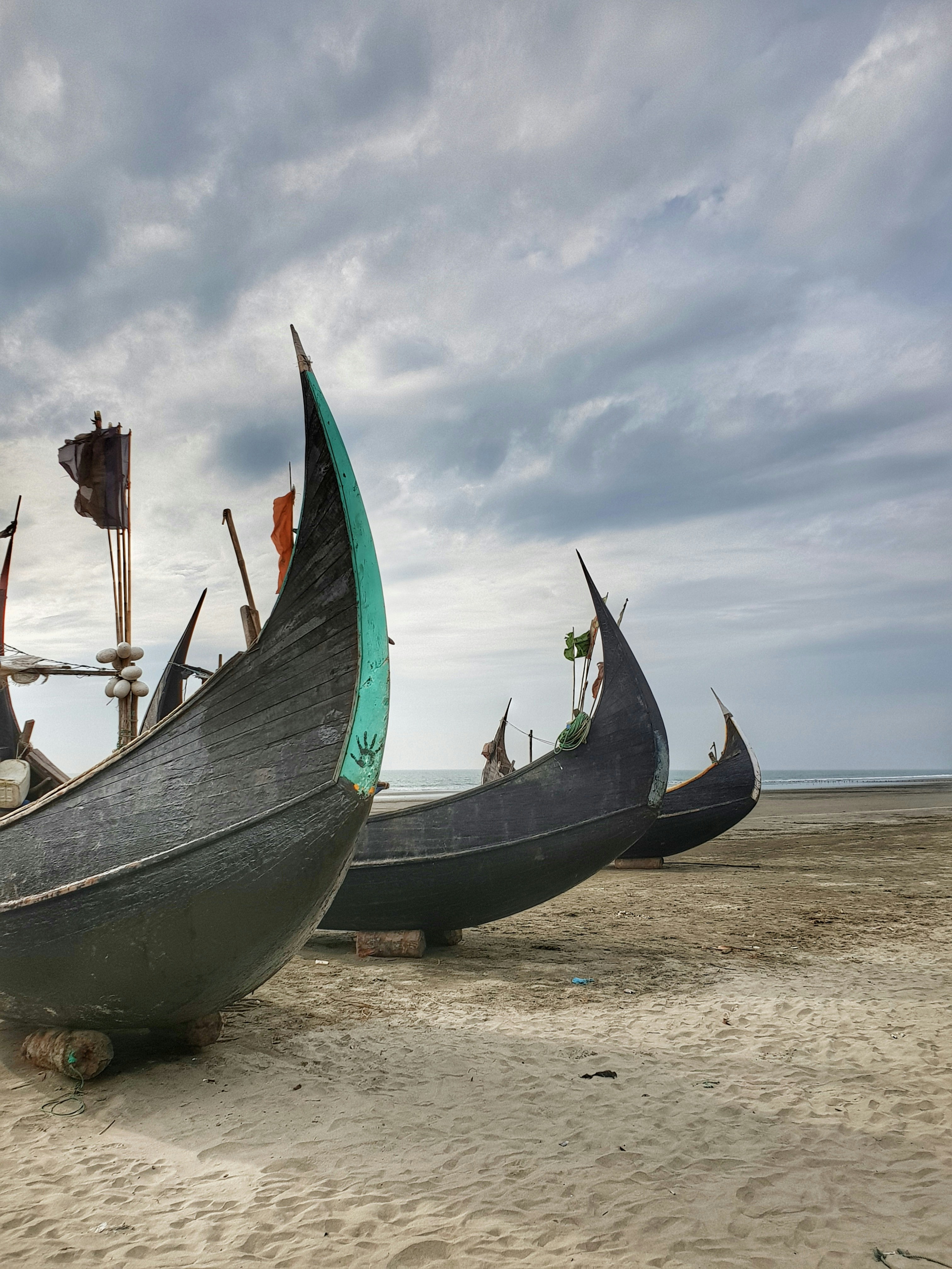 Traditional fishing boats anchored on a sandy shore under a cloudy sky, showcasing the serene coastal lifestyle.