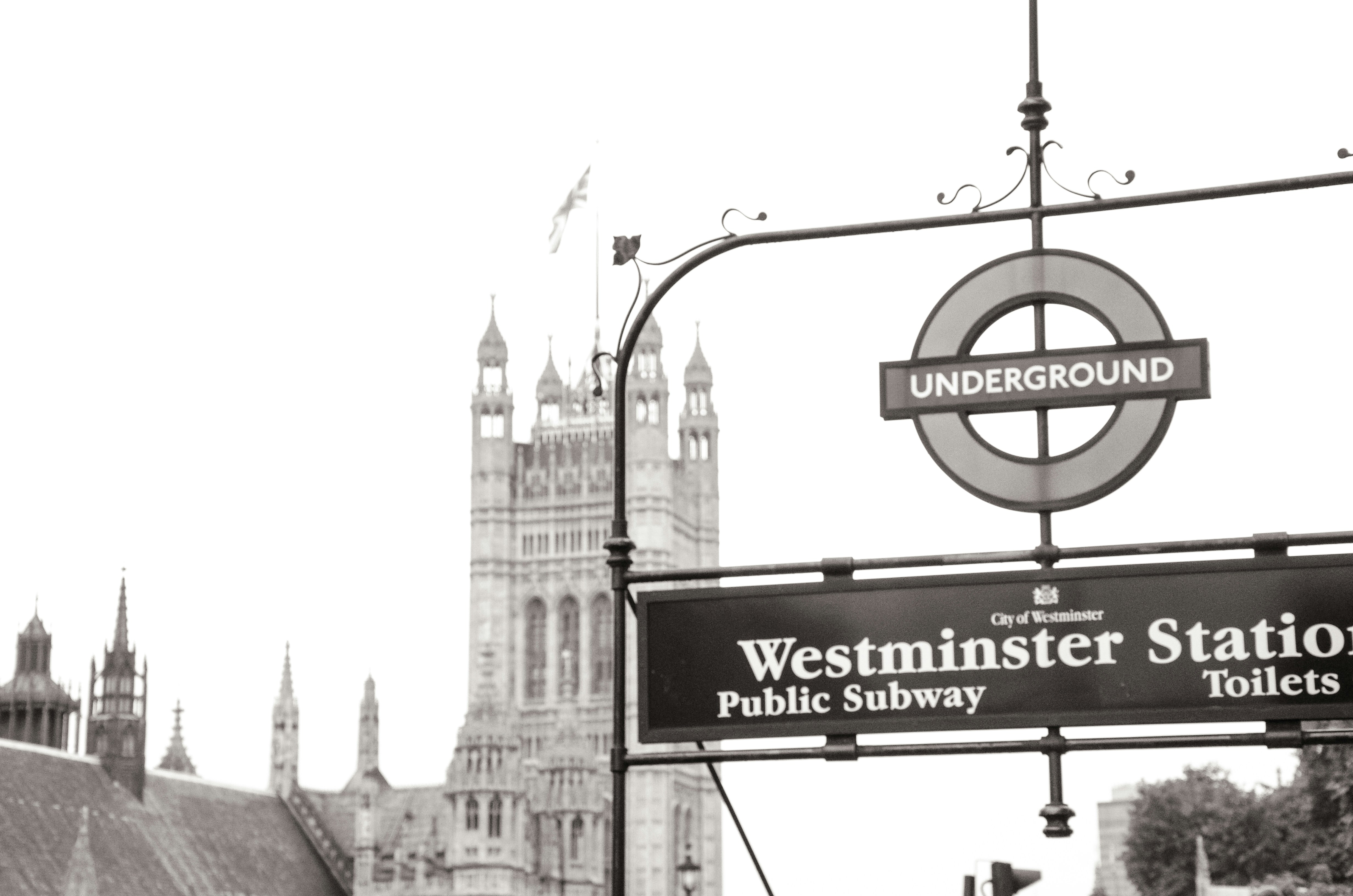 Sign for Westminster Station with iconic Underground logo, framed by the historic architecture of the Palace of Westminster. 