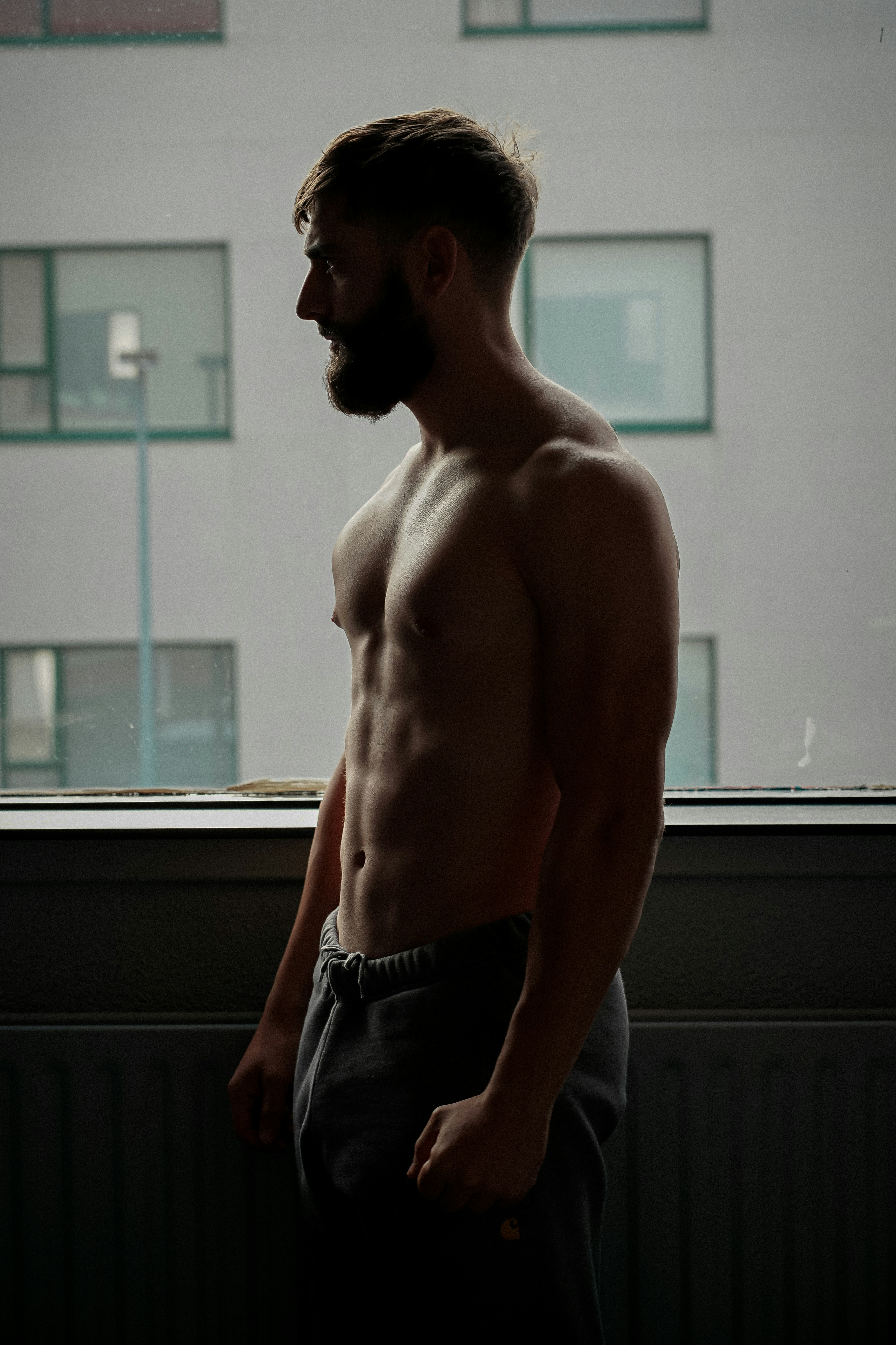 Dormant Strength: A Shirtless Portrait by the Window