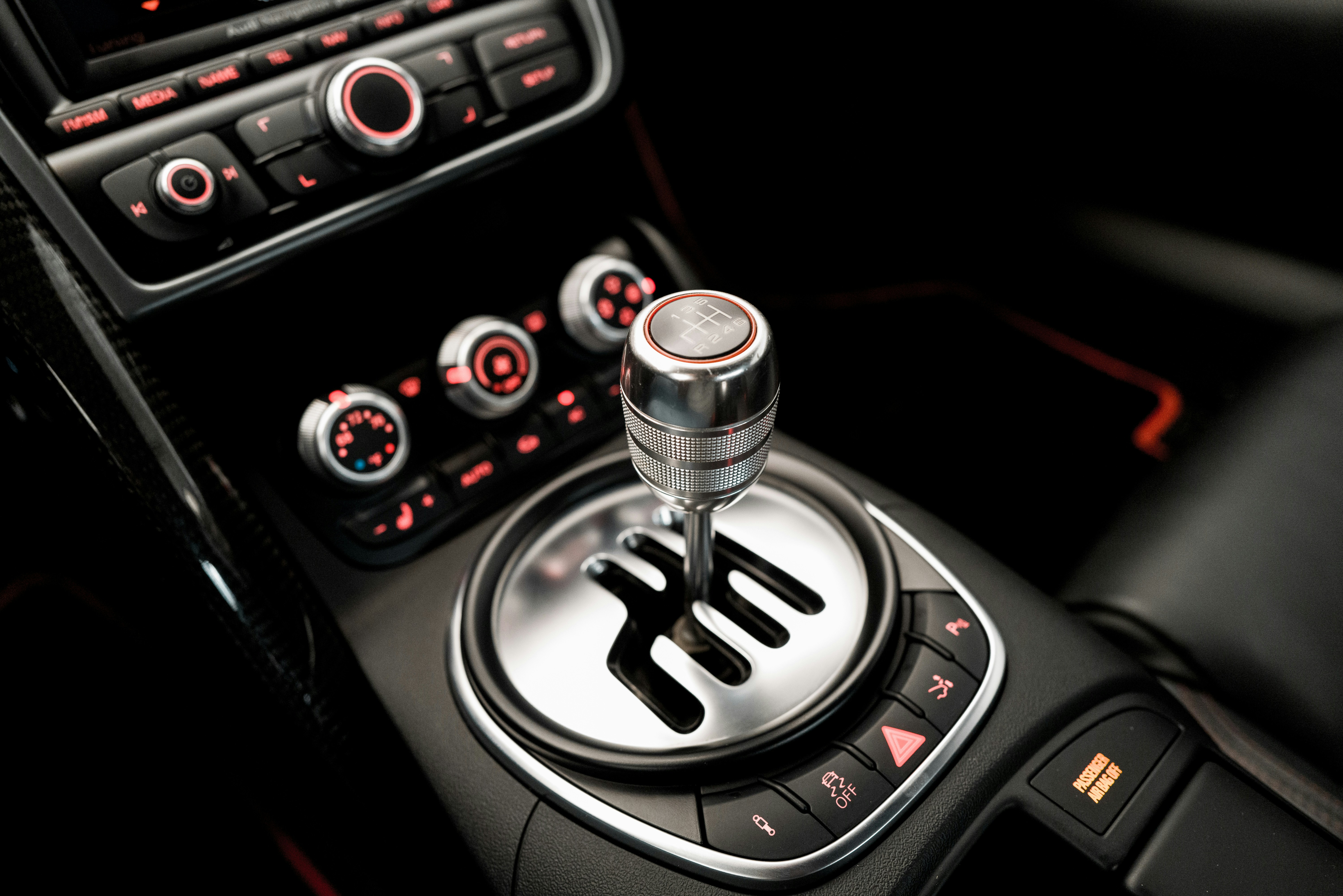Close-up of a sleek gear shifter in a luxury car interior, showcasing the intricate design and modern controls. The contrasting materials enhance the sophisticated aesthetic.