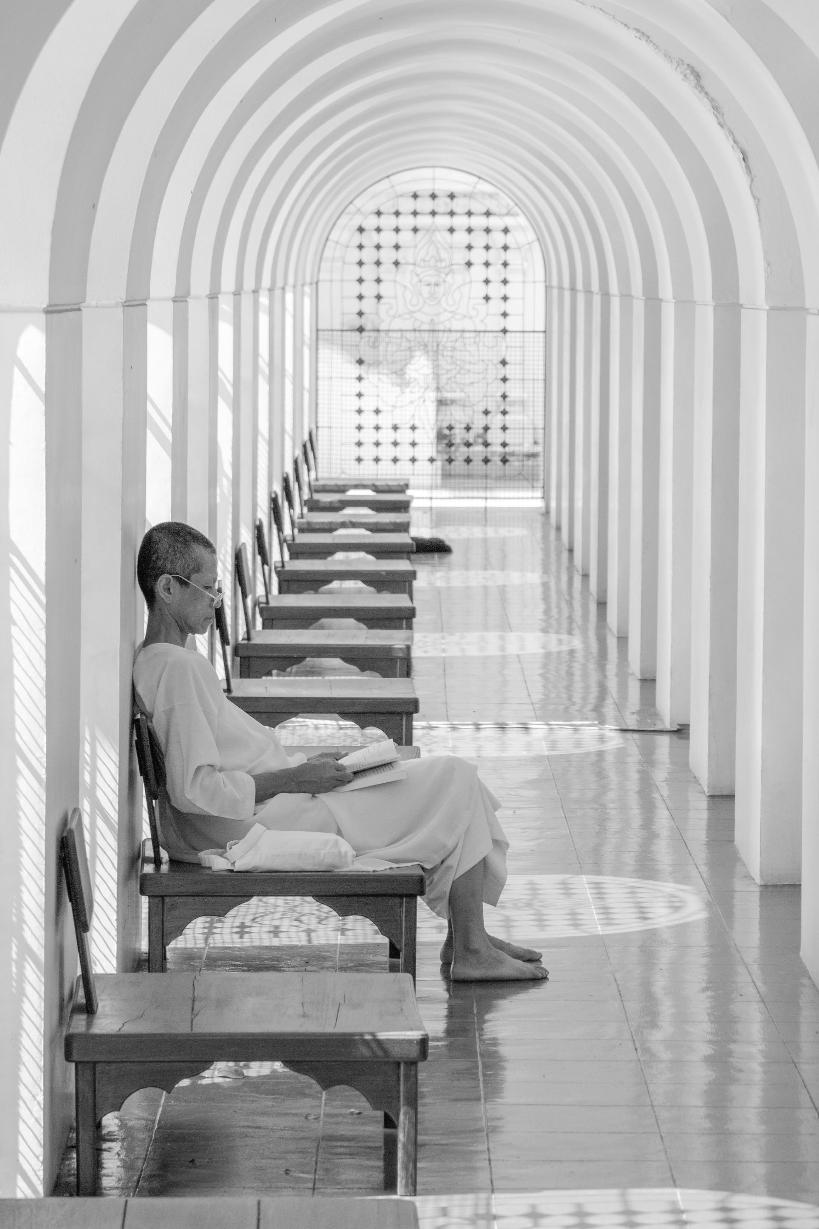 Quiet Reading in a Sunlit Arched Corridor