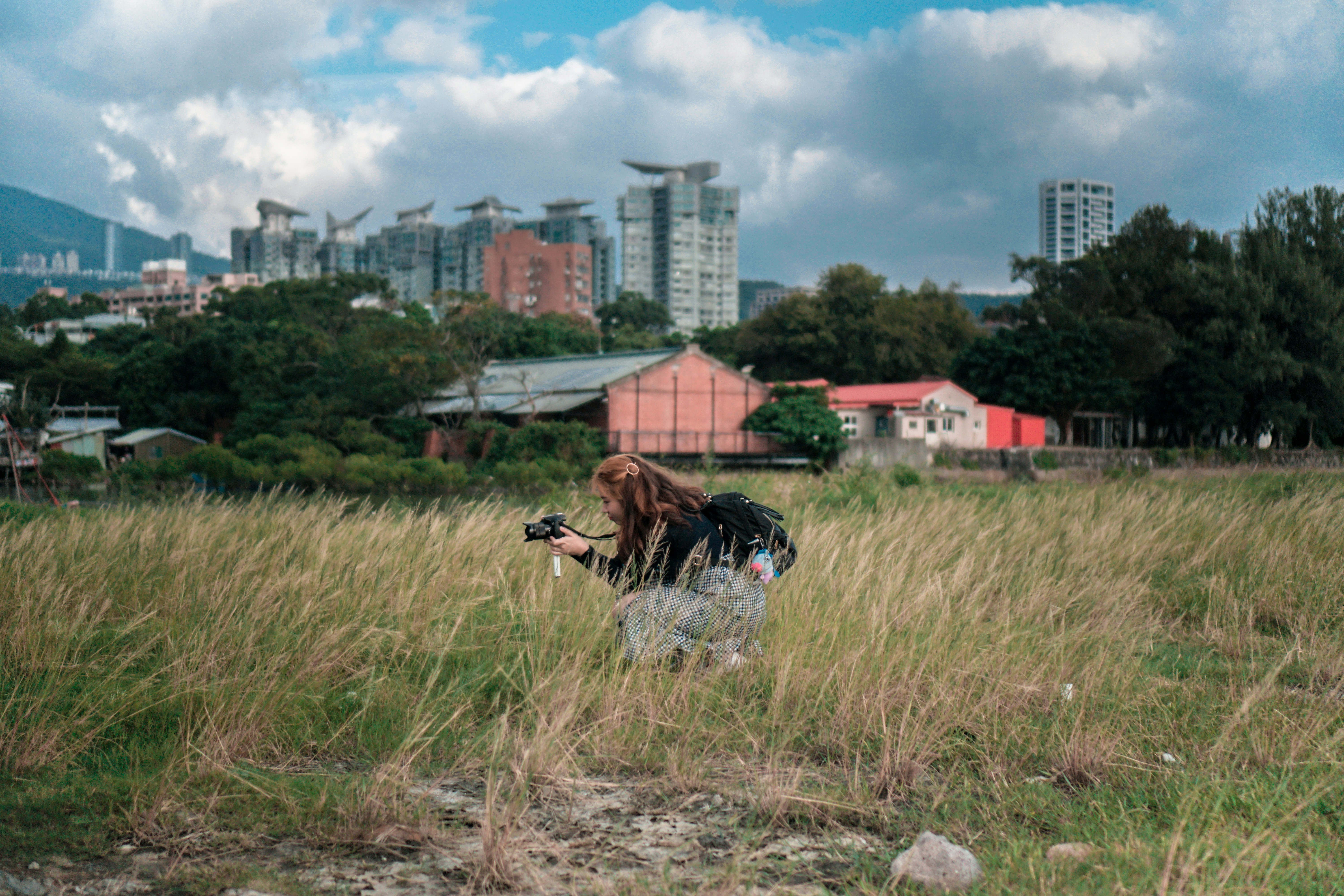 Grassbound Scout: A lone photographer lensing the urban horizon from a windswept field