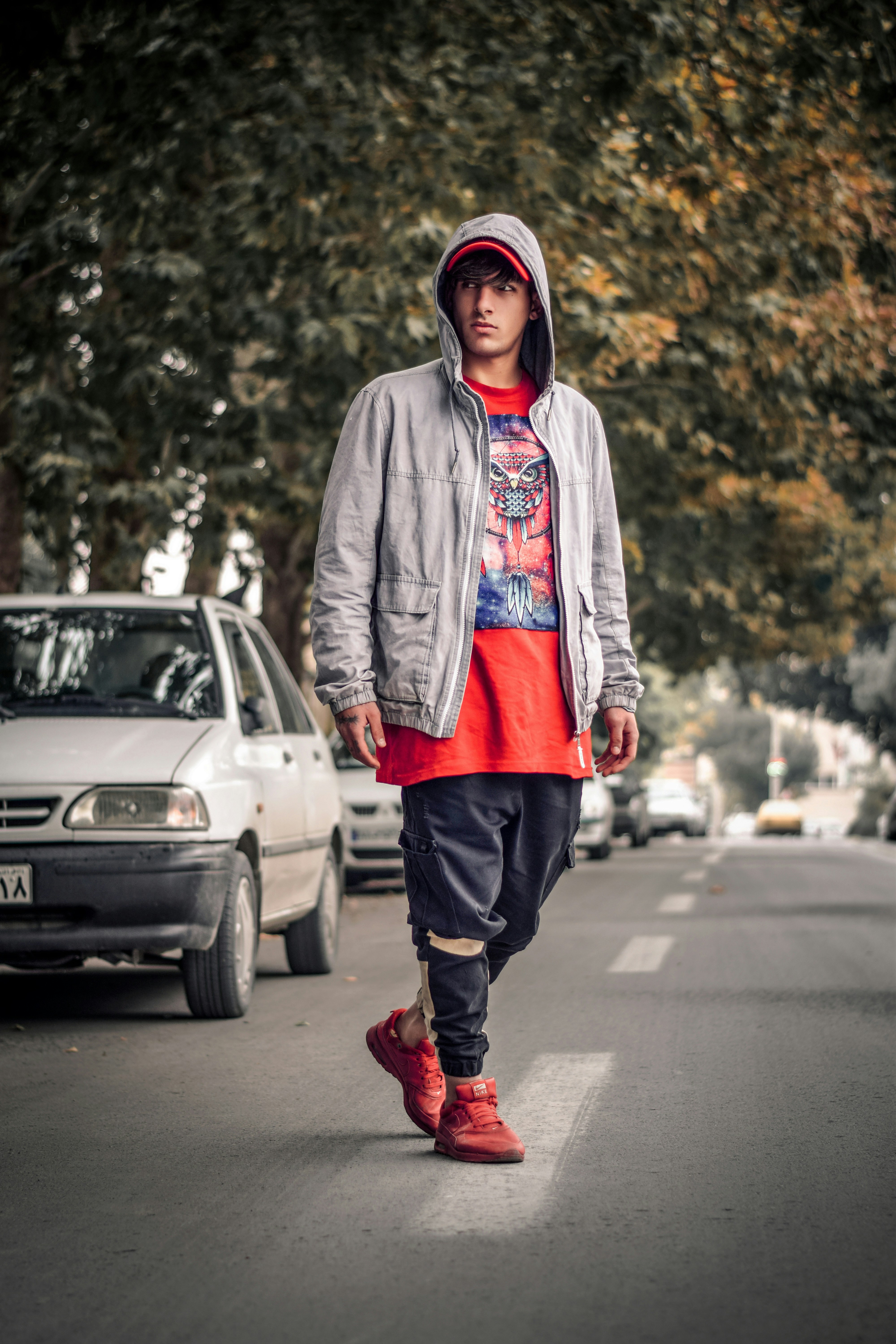 Gray-hooded stride: urban fashion on a leaf-strewn avenue