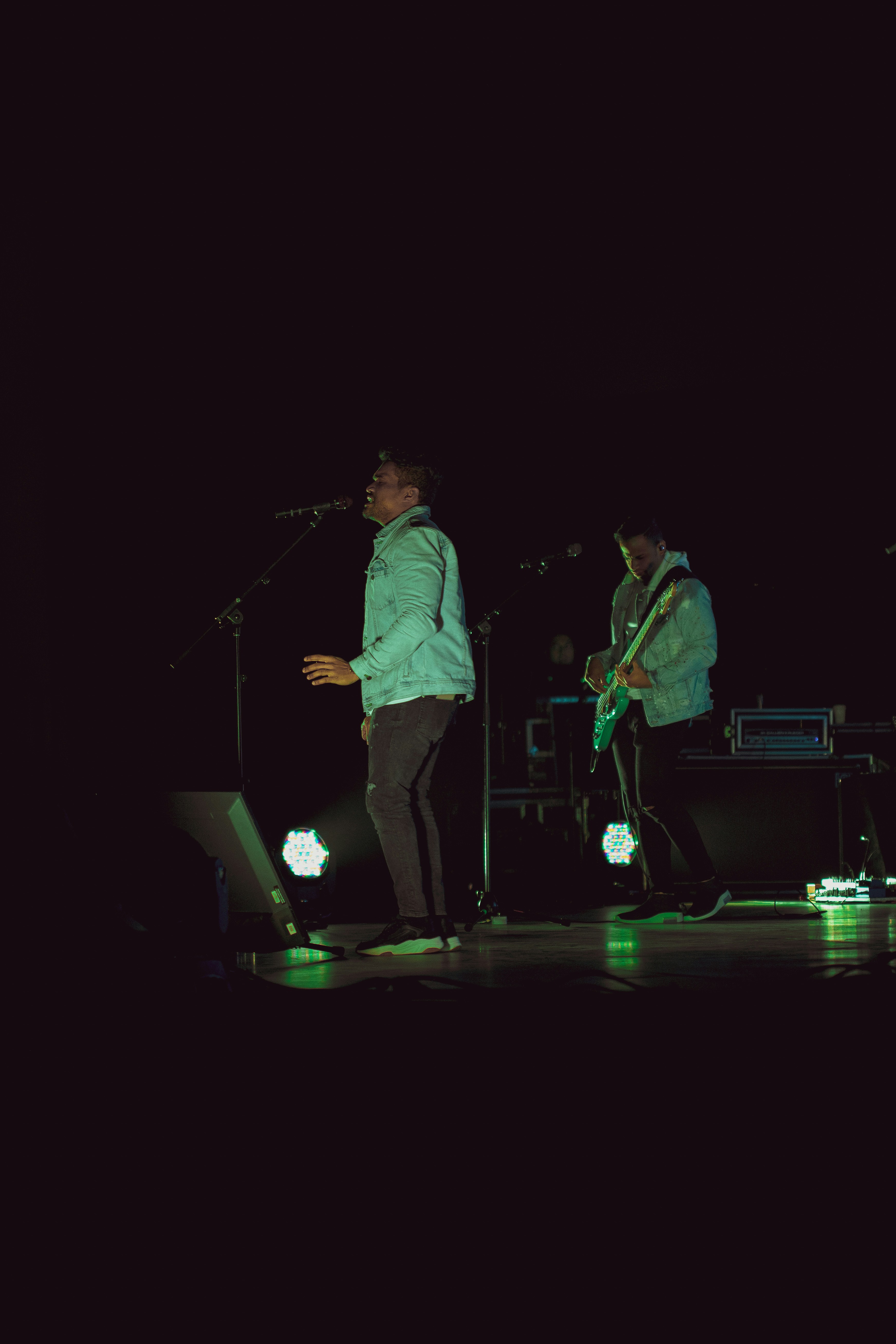 Two men standing while performing on stage during night time photo ...