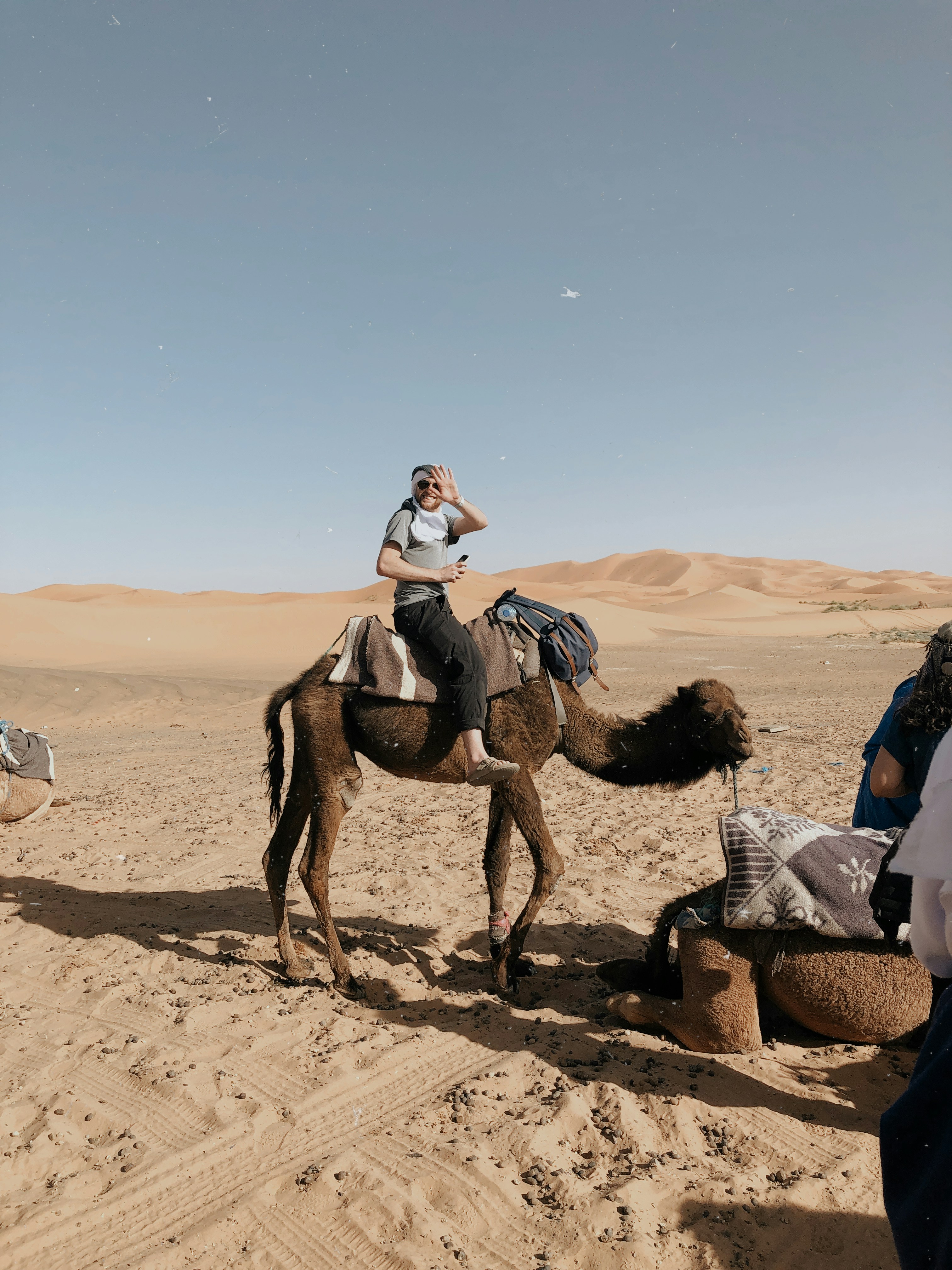 Man riding brown camel while waving his hand during daytime photo ...