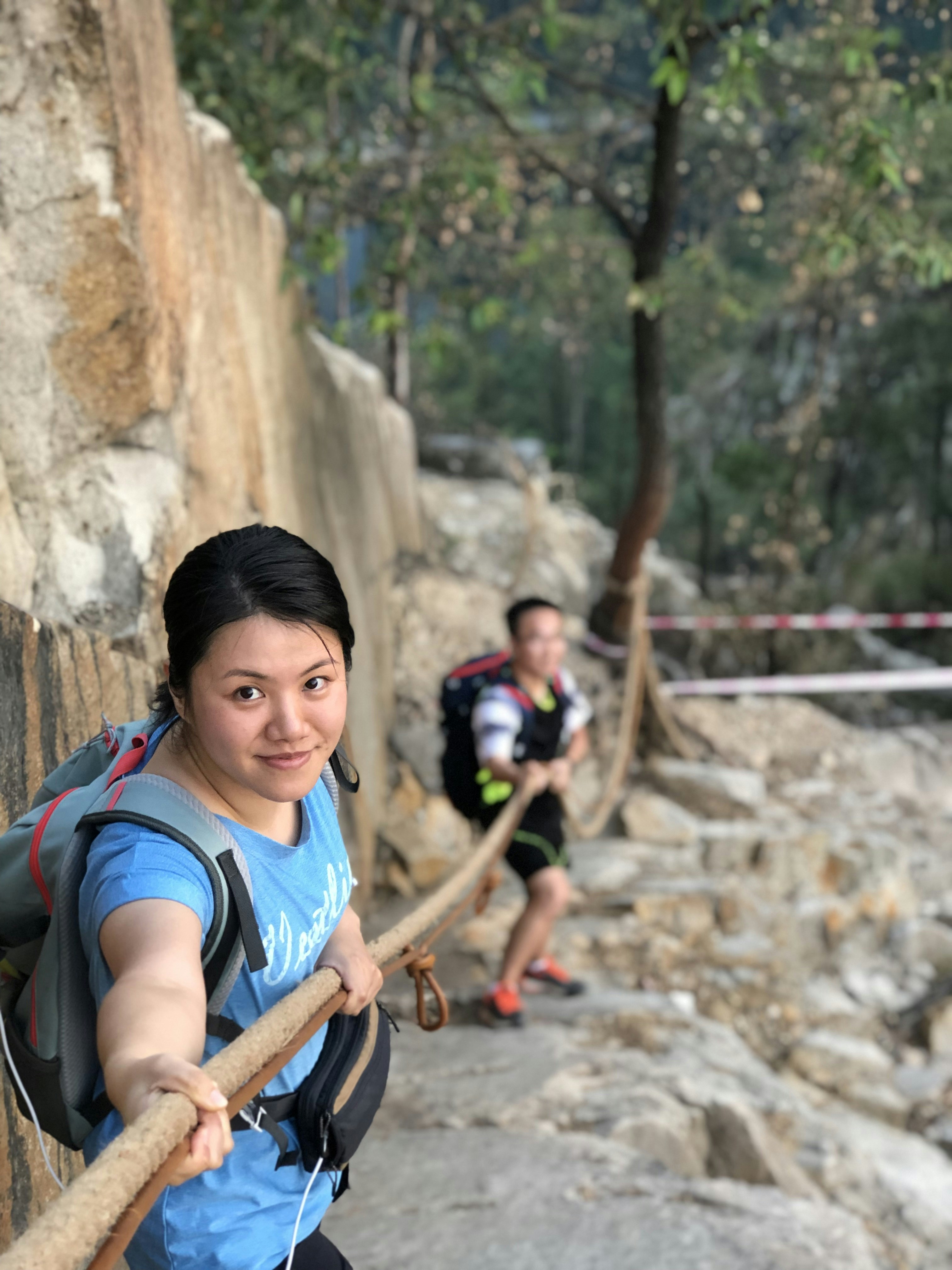 Trailbound Confidence: Woman Leading the Climb on a Narrow Ridge