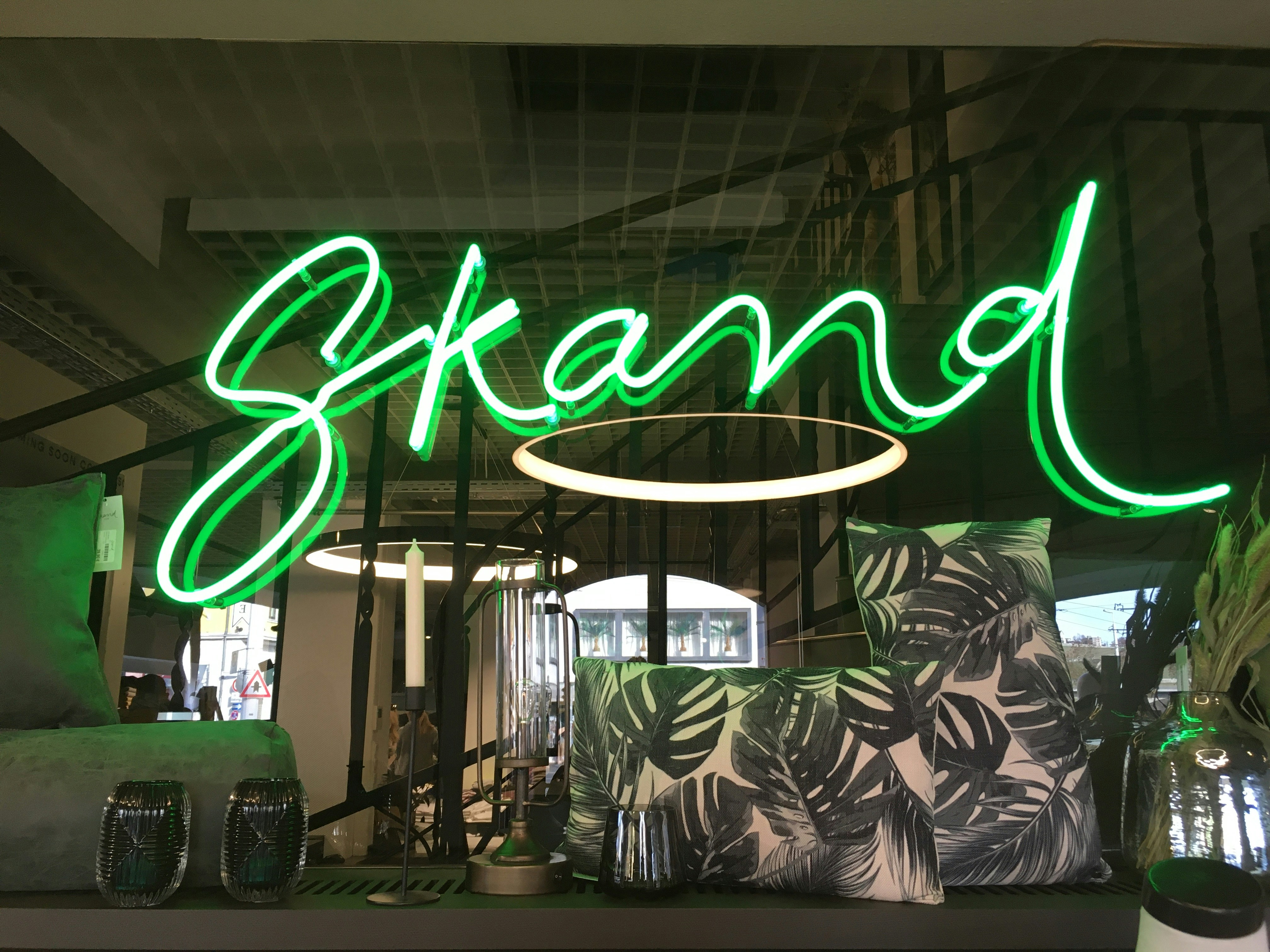 Neon Skand Sign Over a Leaf-Patterned Lounge