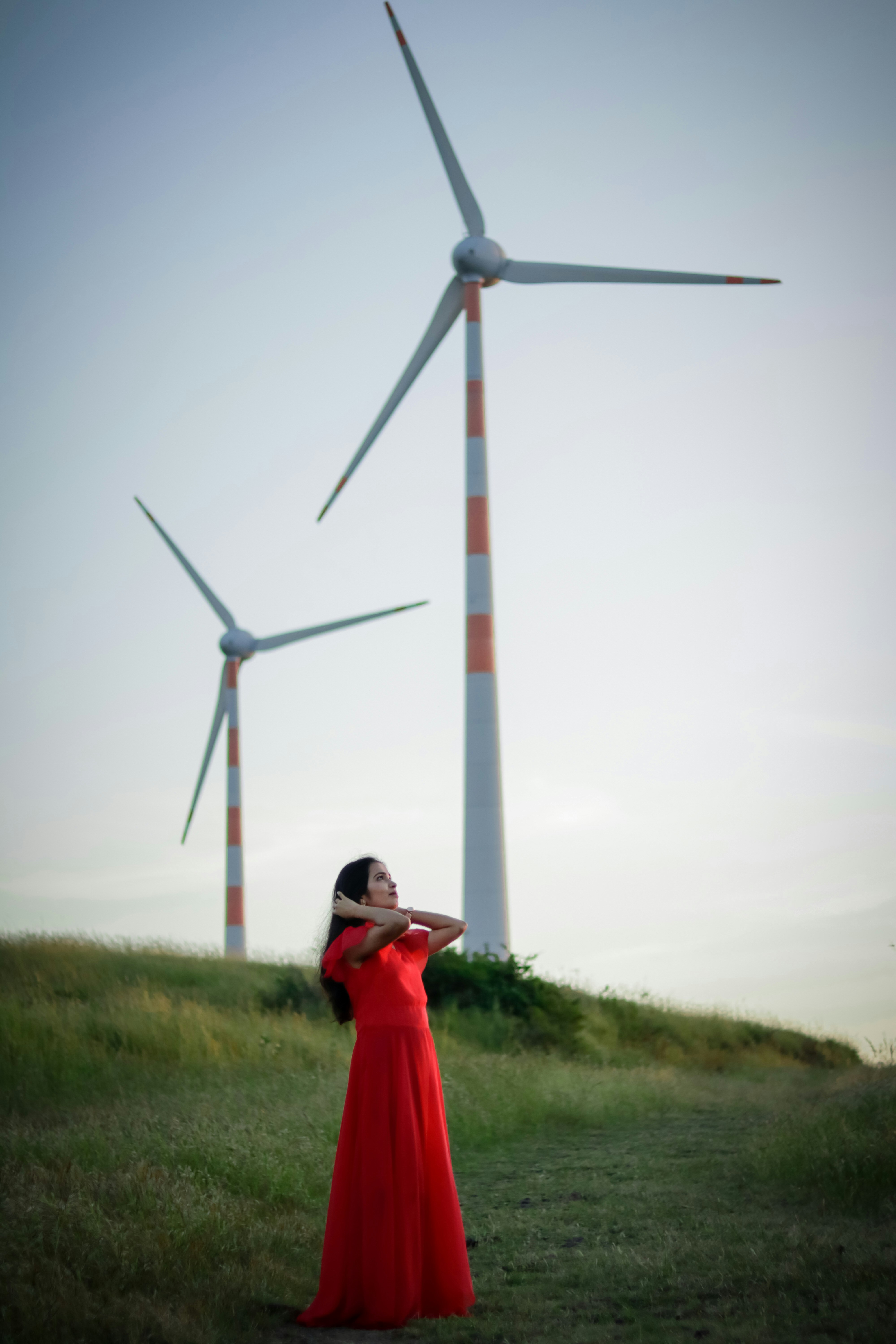 Red dress beneath wind farms: a portrait by rolling dunes