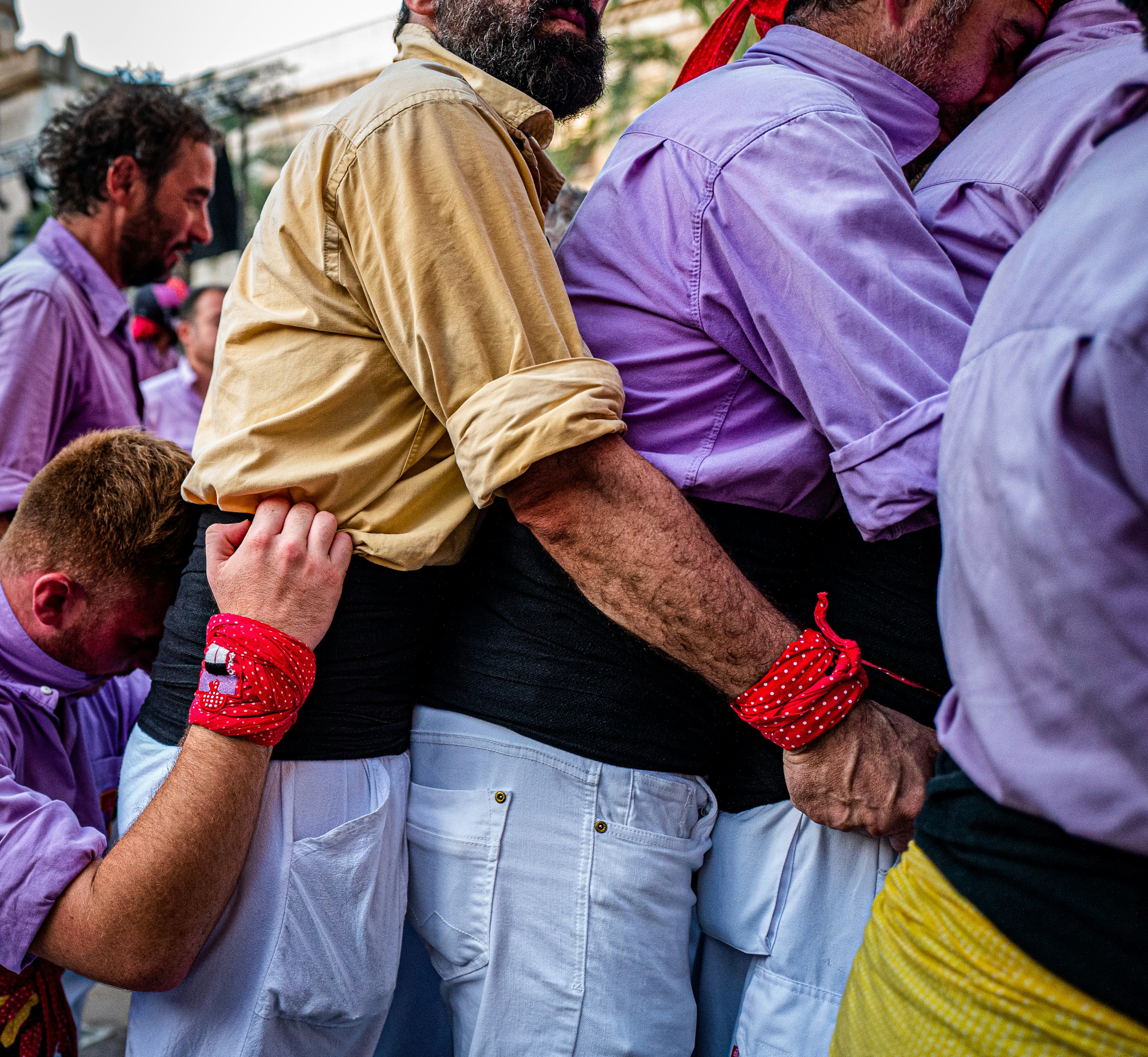 Tangled Bandage Reds: A Row of Tied Wrists in a Festival Circle