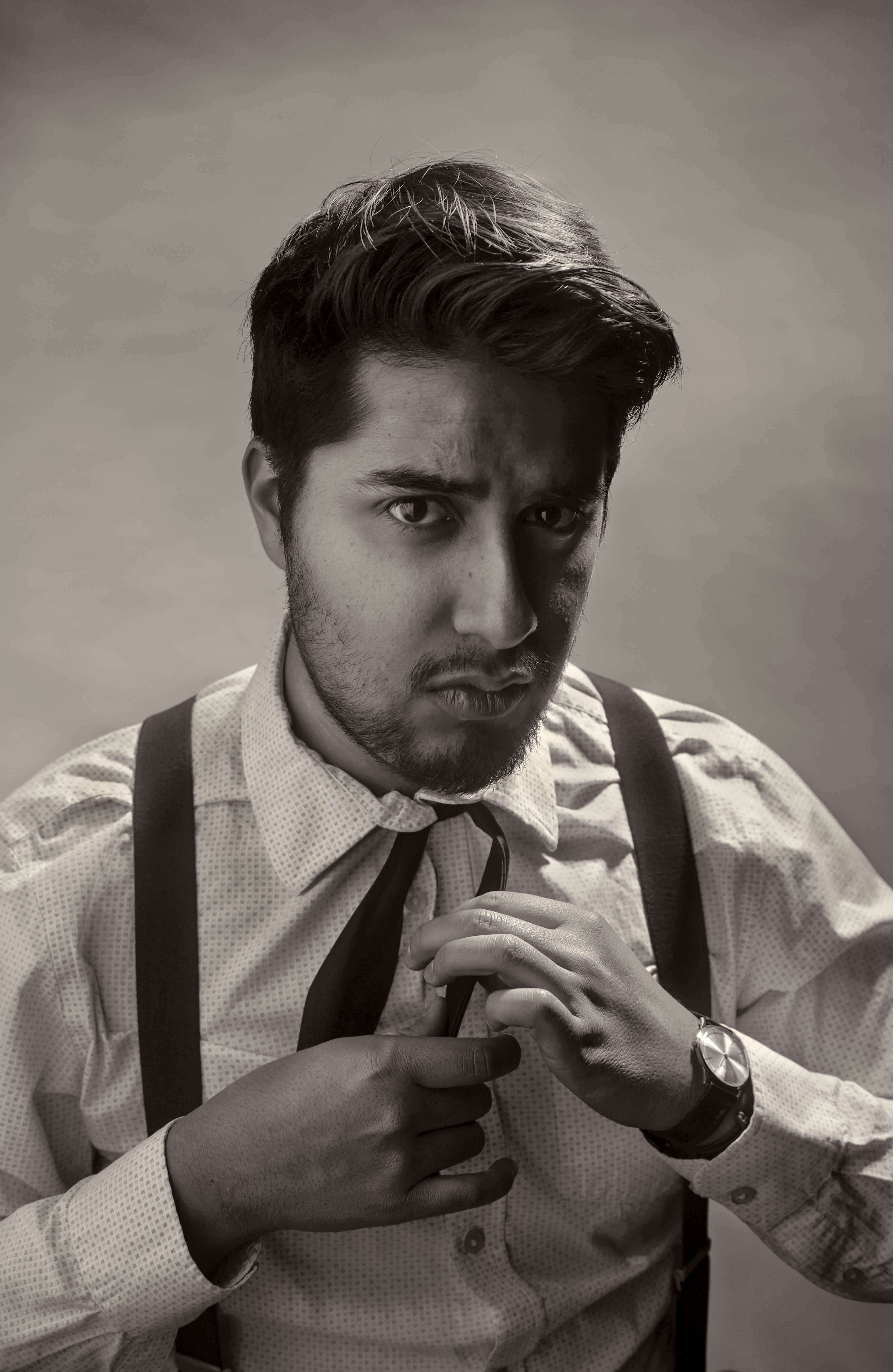 Monochrome Poise: A Gentleman Tightens His Tie Under Studio Light
