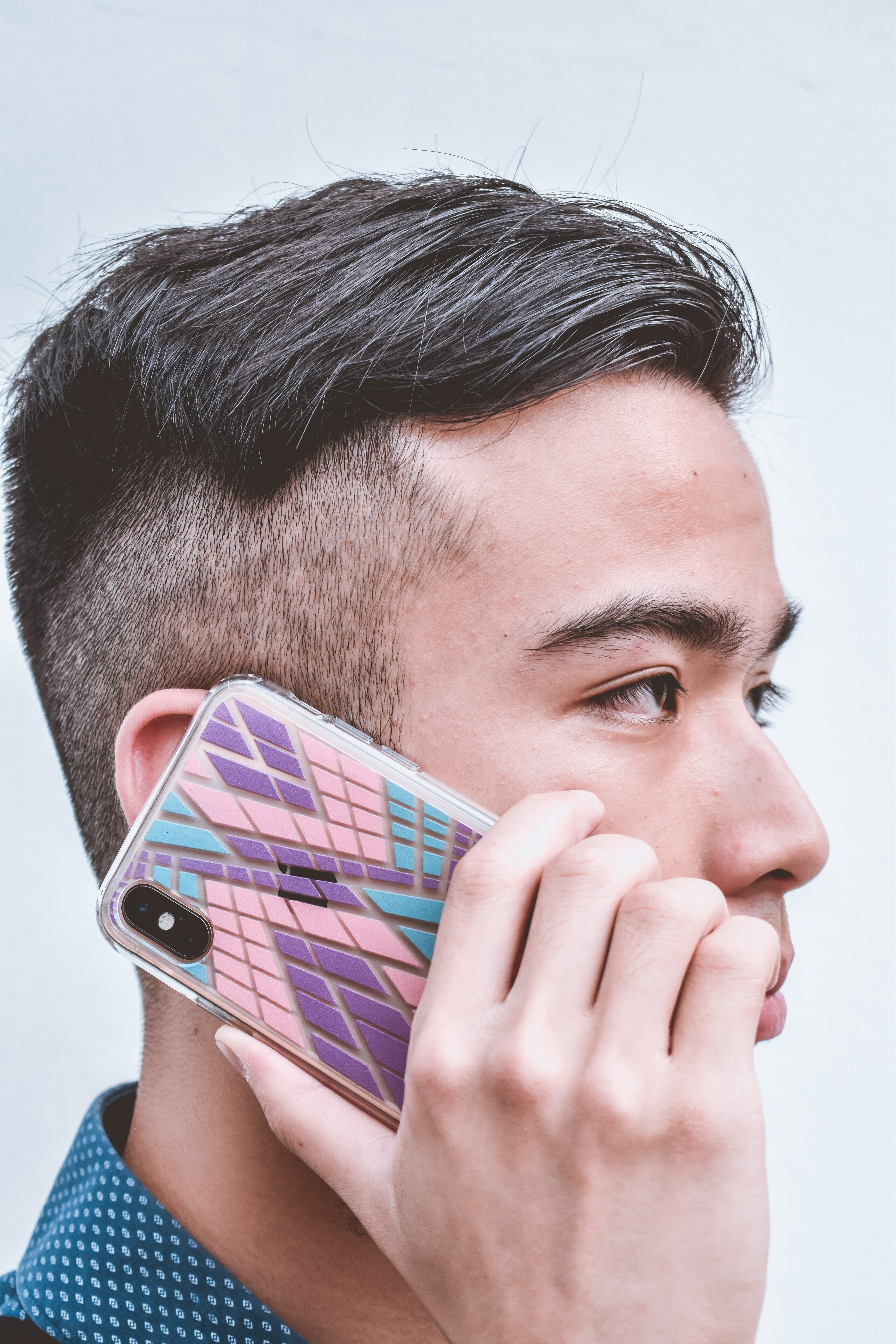Young man engaged in a phone conversation, showcasing a colorful phone case against a minimalistic background.