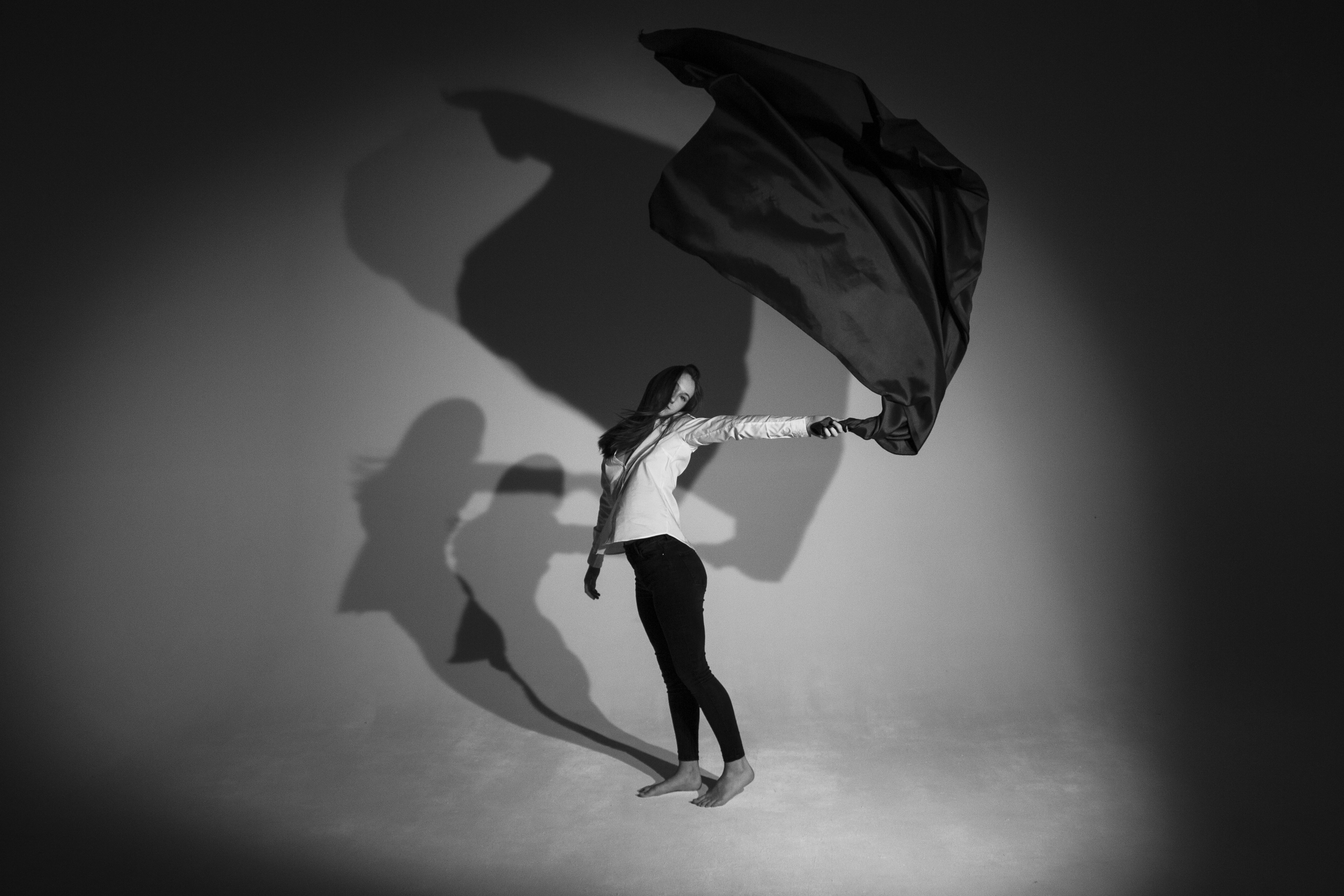 Grace in Shadow: A Dancer Commands the Stage with a Veiled Flag