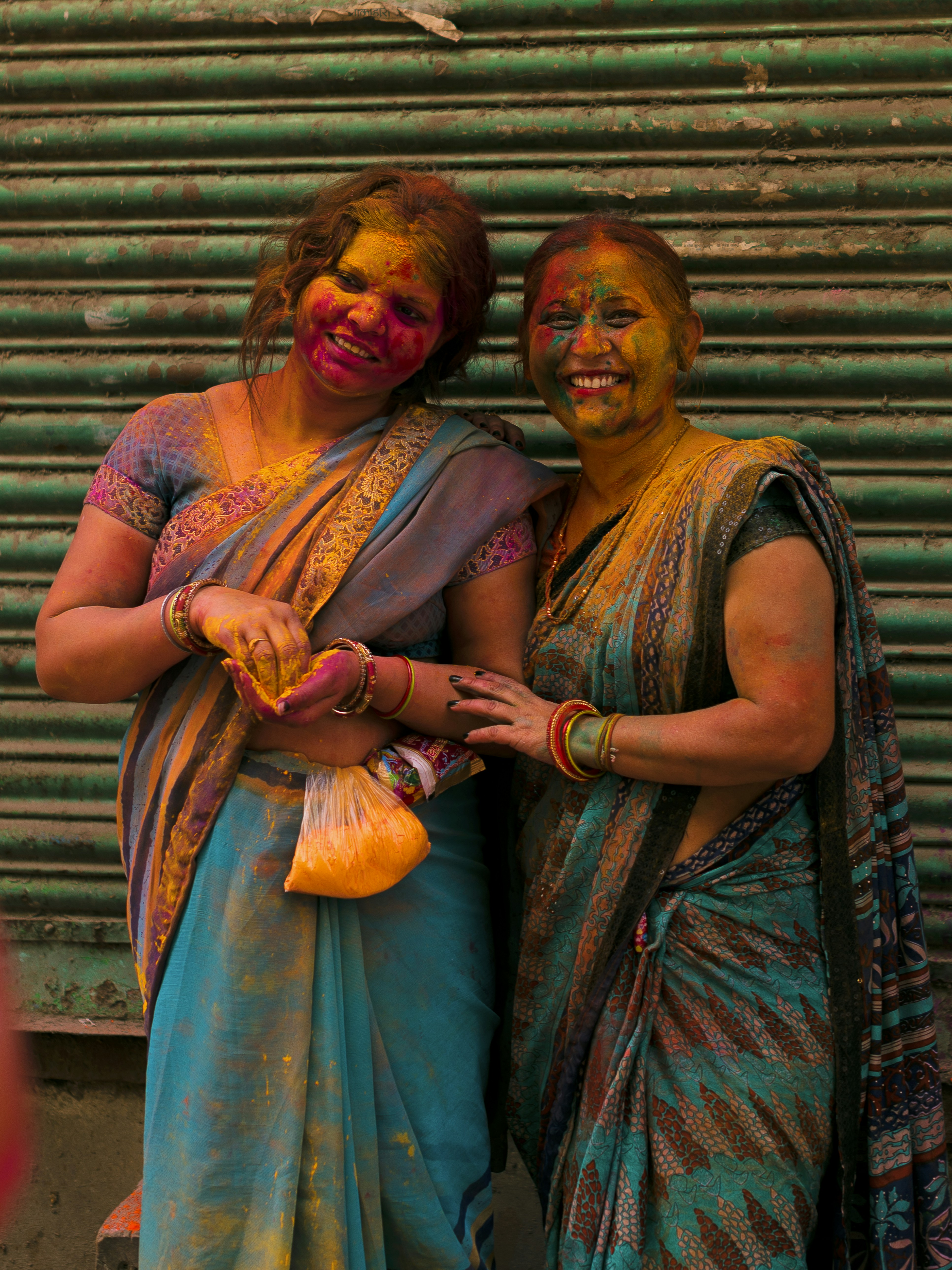 Holi Duo: Colorful Joy in a Corrugated Backdrop