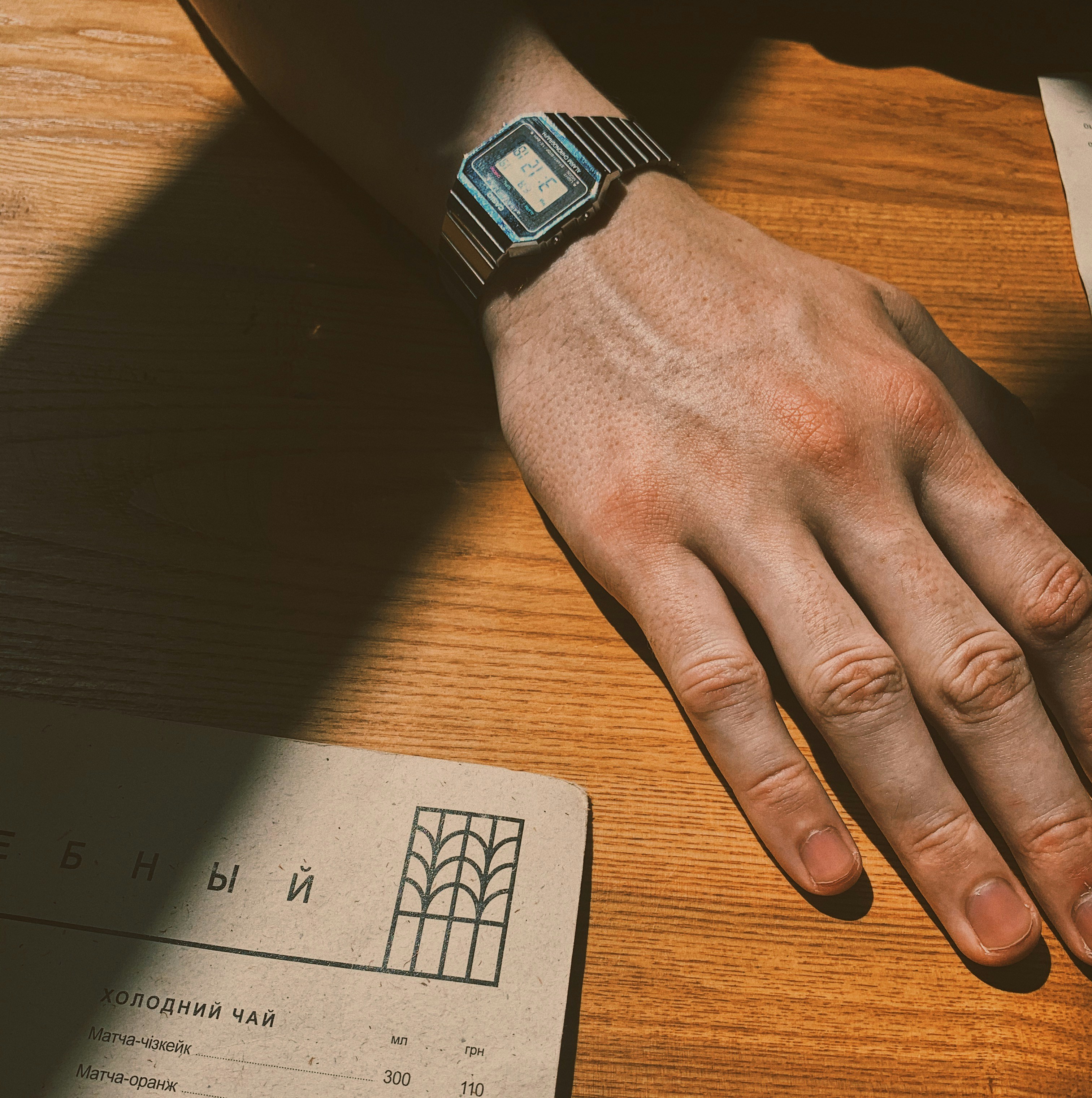 Sunlit Steel on Wood: Close-Up of a Digital Watch on a Hand