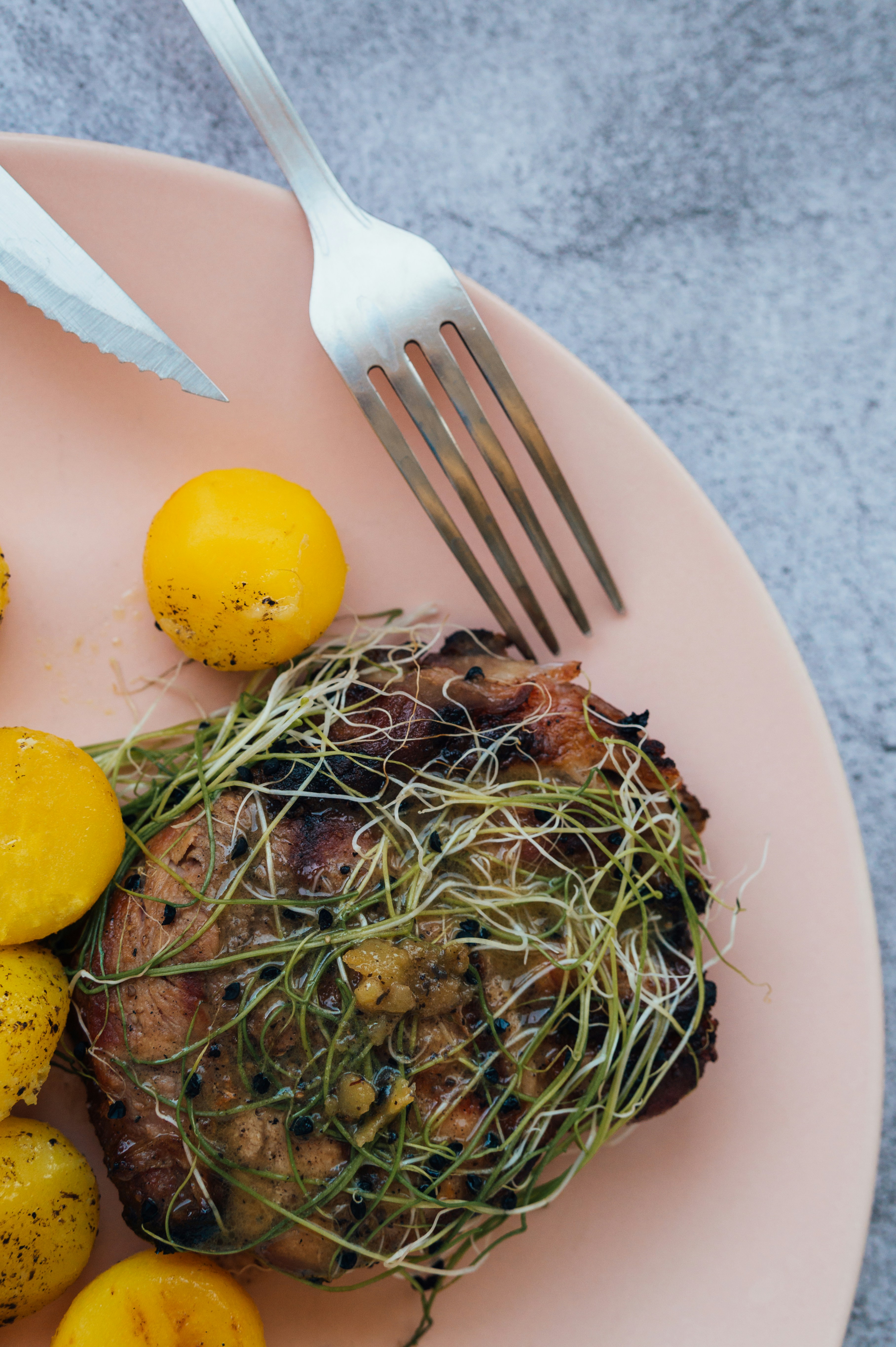 Steak with potatoes on pink plate at the gray background