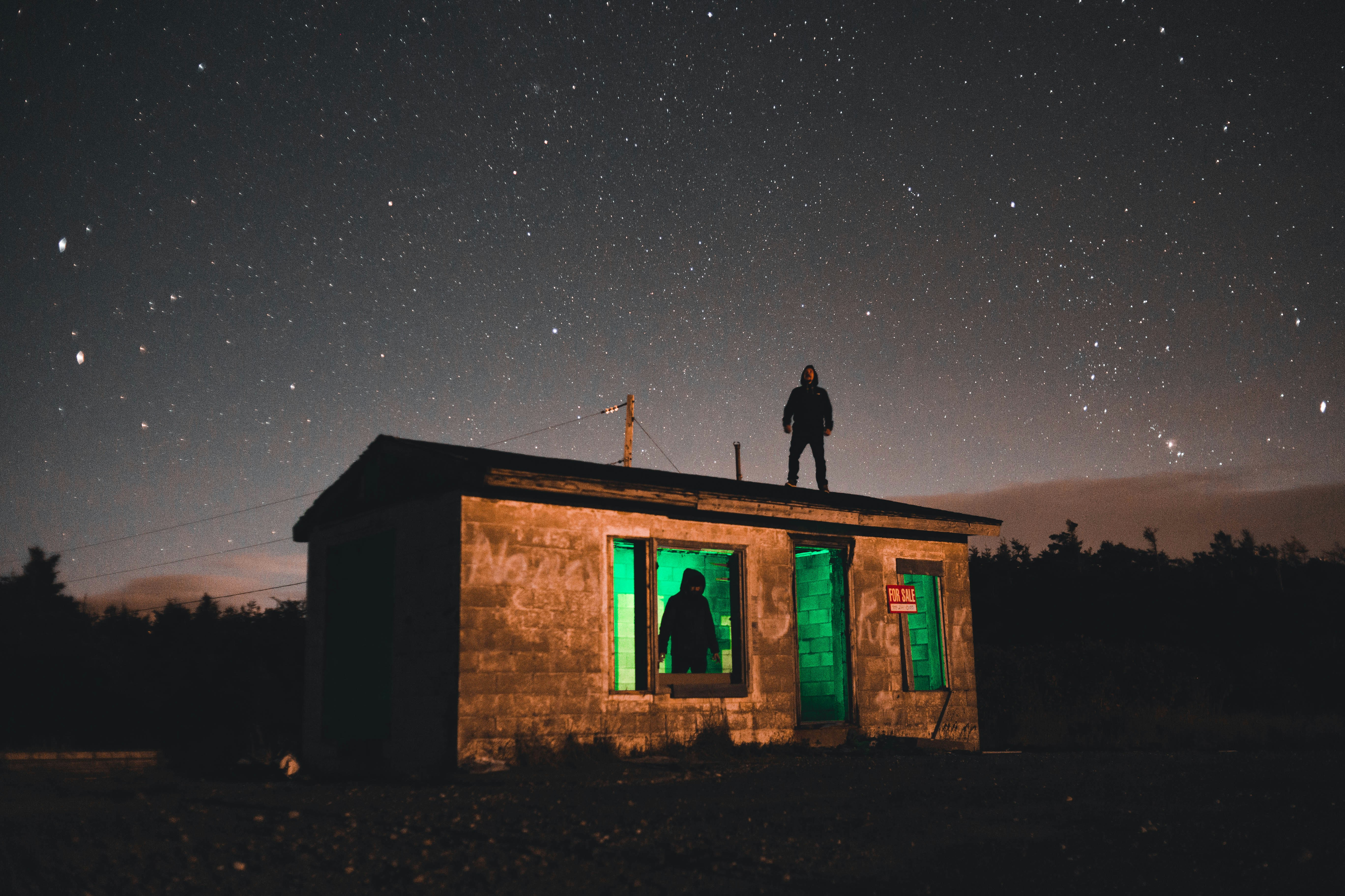 Stars Over a Lit Cabin: Night Sky with Figures on a Flat Roof