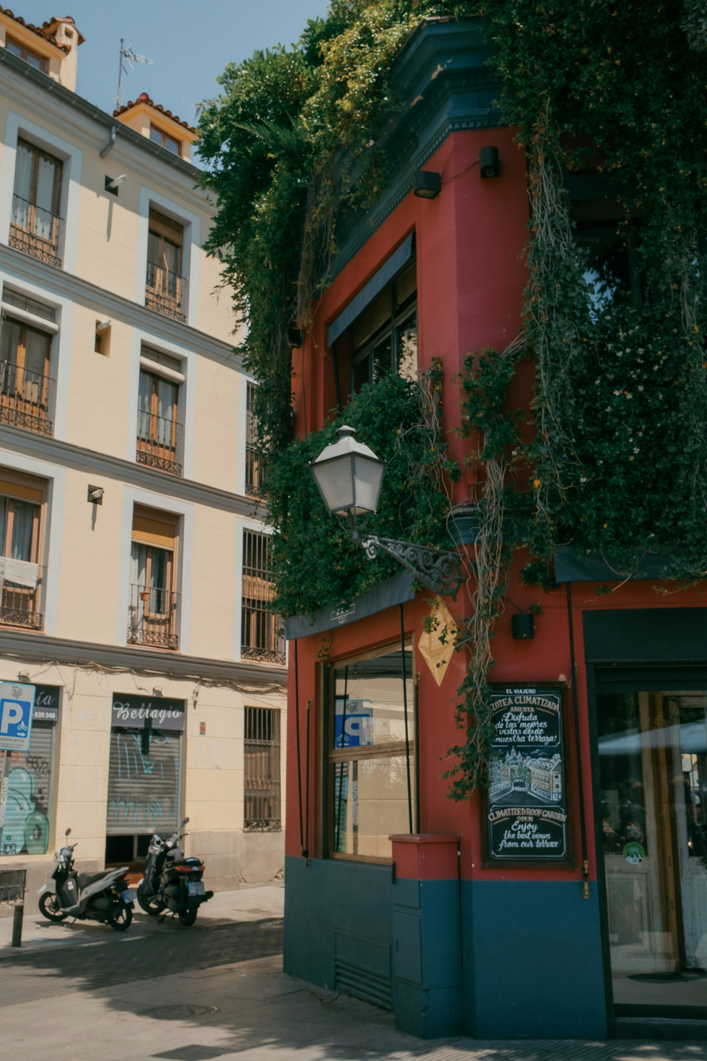 Colorful building adorned with lush greenery and a vintage lamp, showcasing a vibrant street scene in a bustling neighborhood.