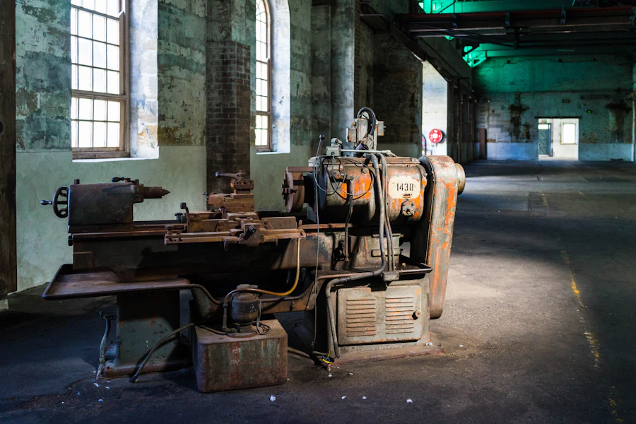 Rusty lathe machine resting in an abandoned industrial space, illuminated by soft light filtering through high windows.