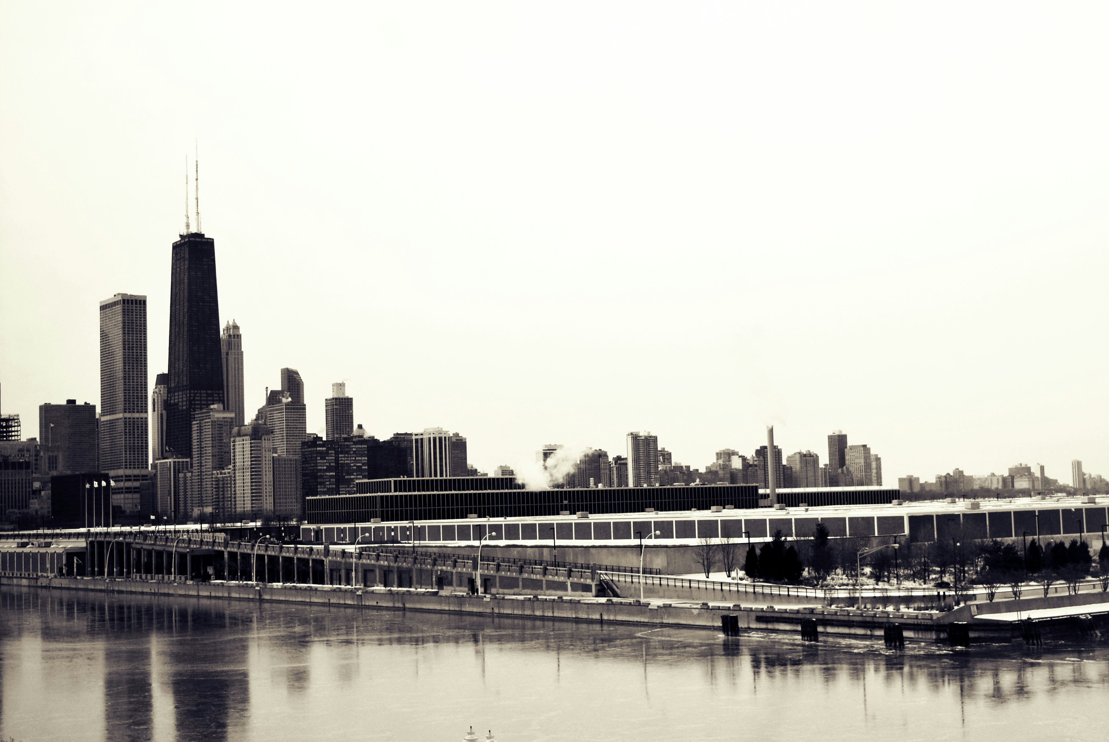 Silhouetted skyline of Chicago featuring the iconic Willis Tower, with reflections on a calm water surface below.