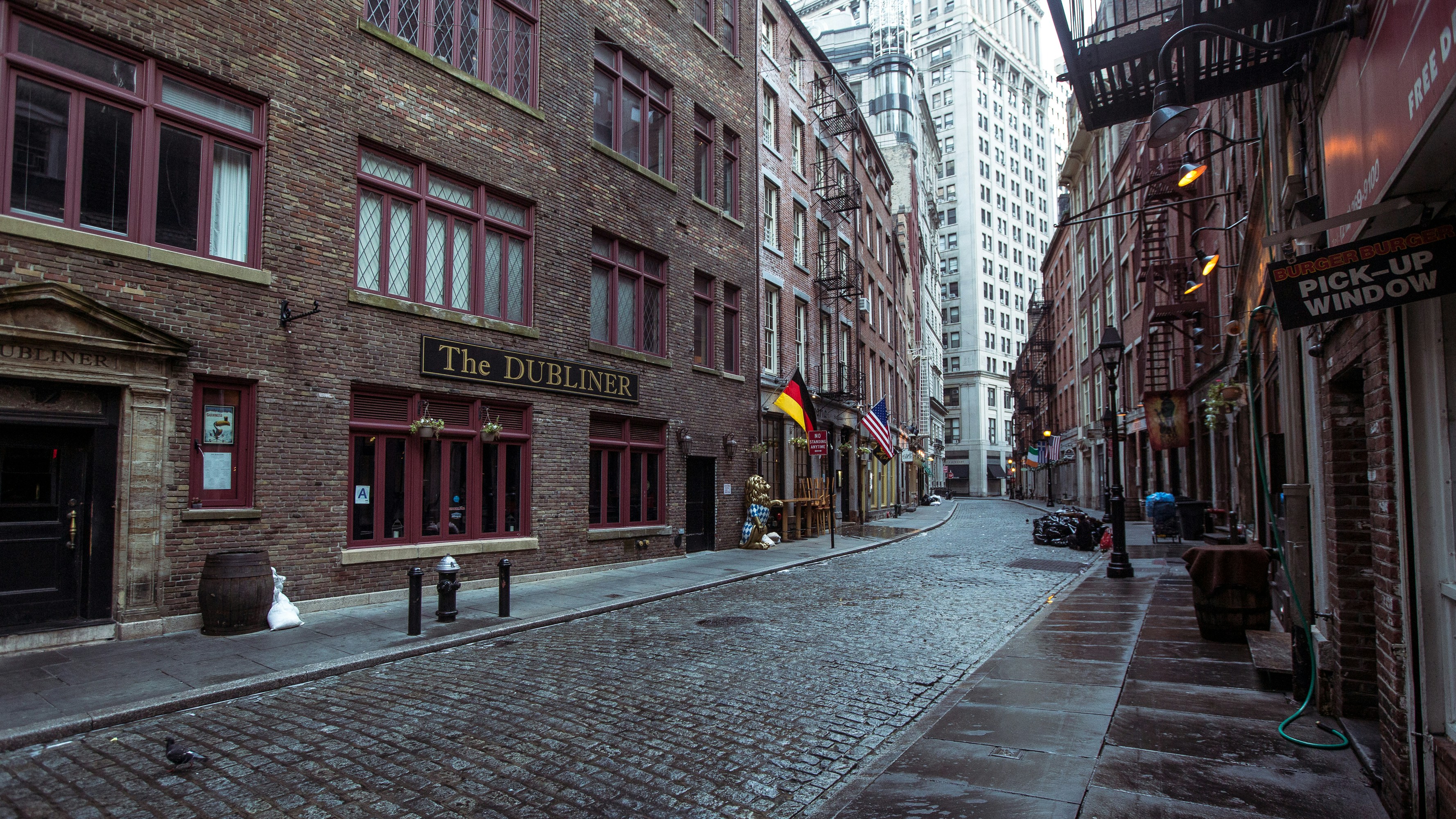 Historic cobblestone street featuring The Dubliner pub and vibrant flags, evoking a sense of nostalgia in an urban setting.