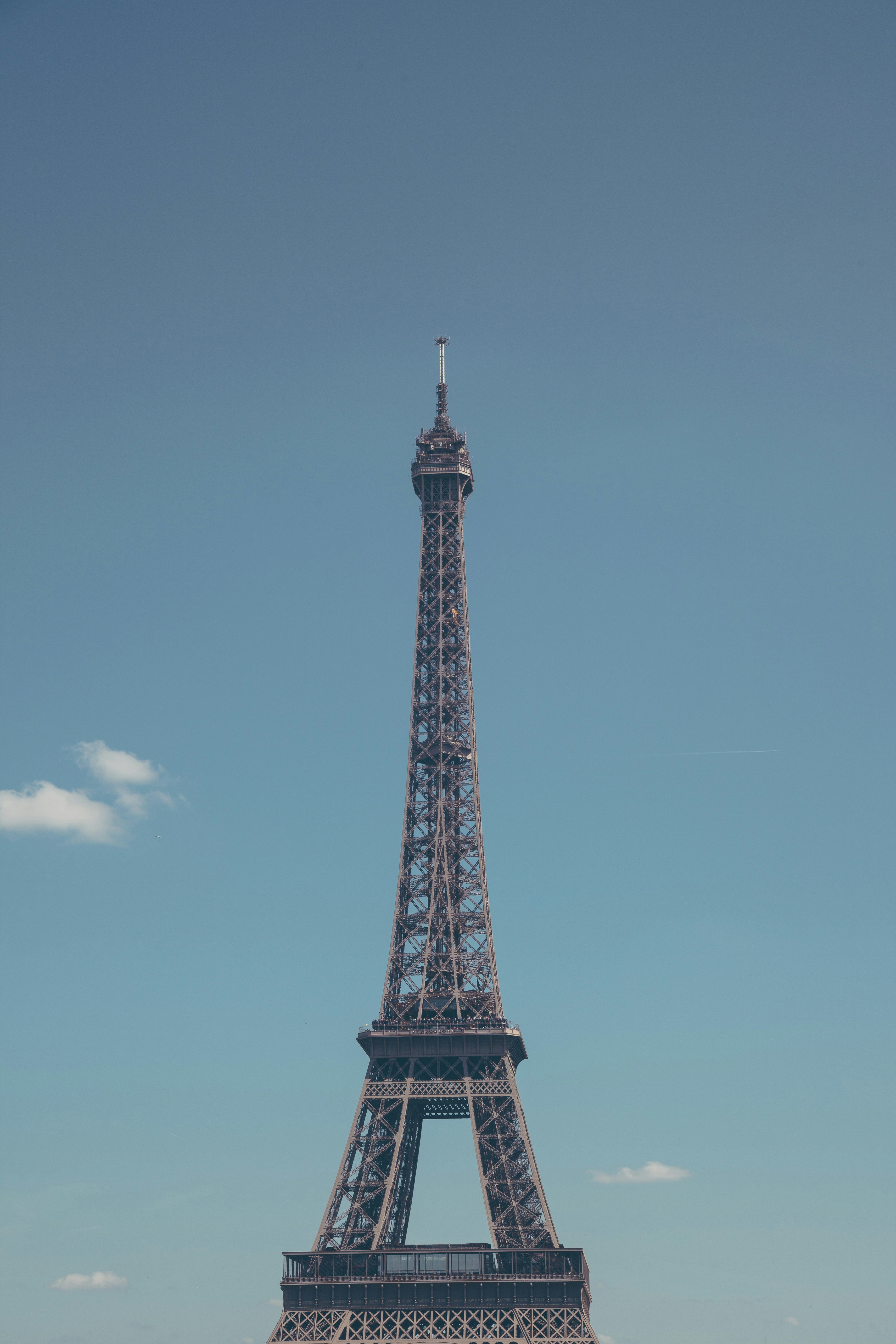 Eiffel Tower rising majestically against a bright blue sky with scattered clouds.