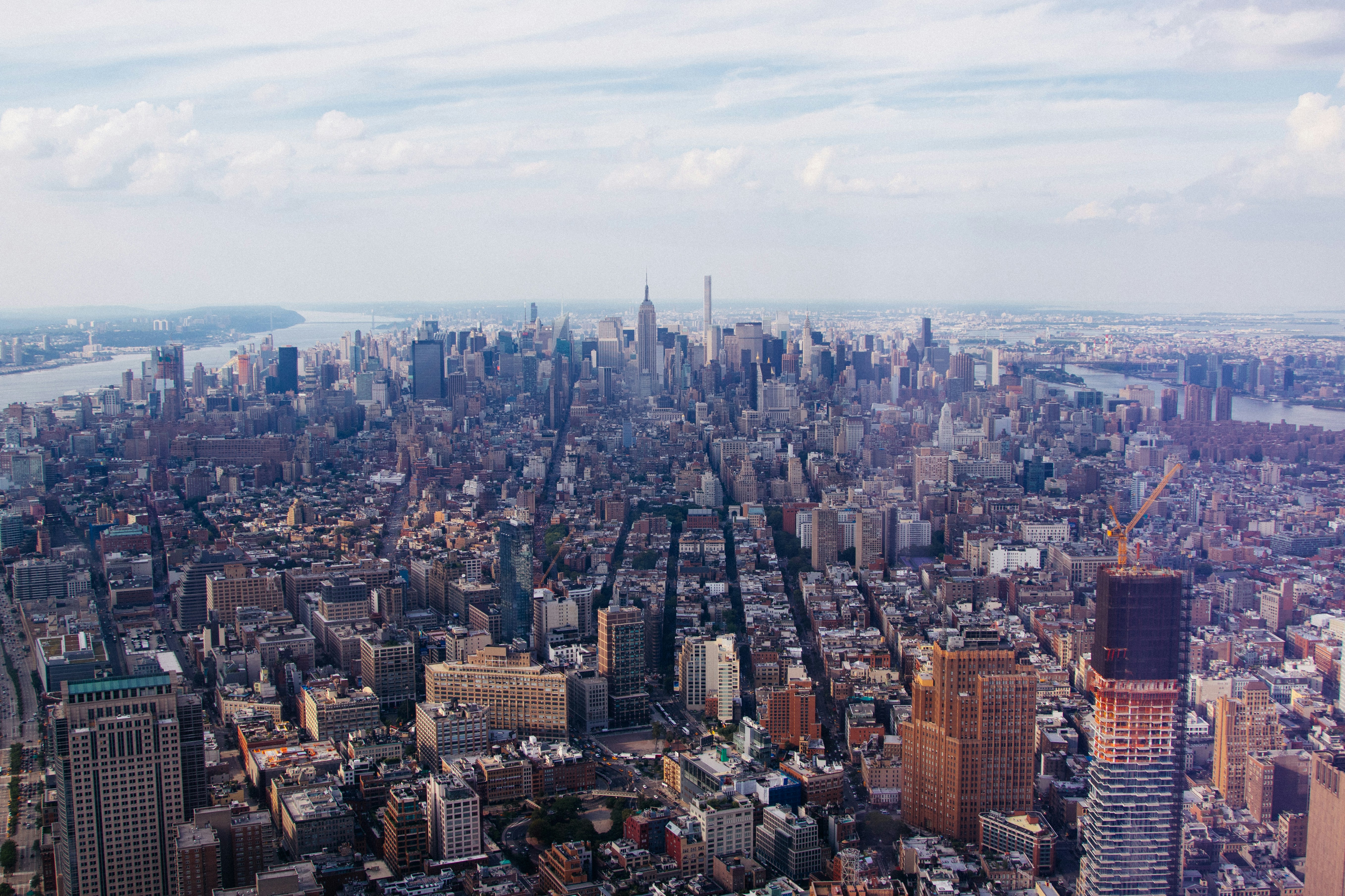 Expansive aerial view of a dense cityscape with skyscrapers stretching towards the horizon under a cloudy sky.