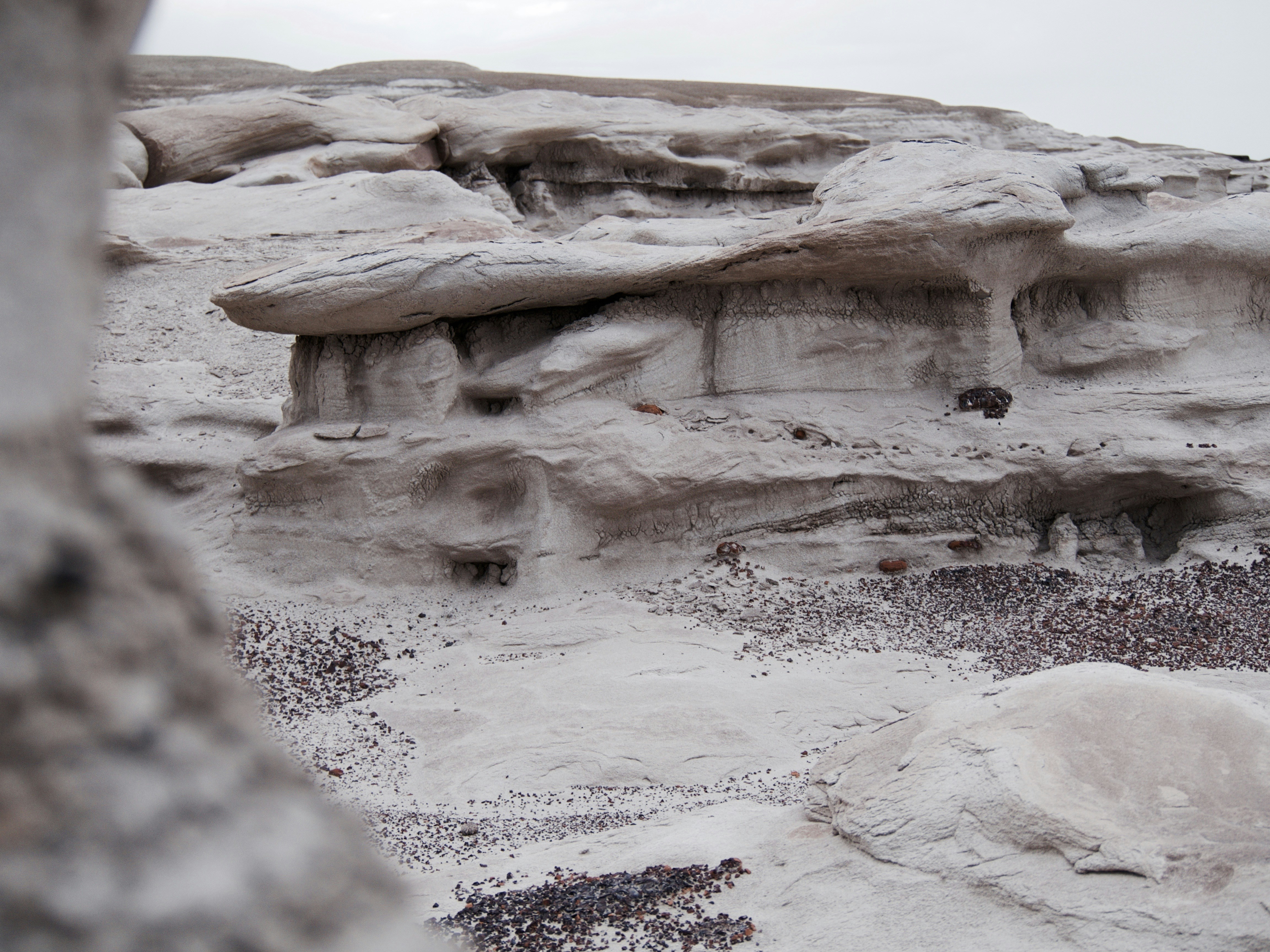 Intricate rock formations shaped by erosion, revealing layers of history in a stark, monochromatic desert setting.