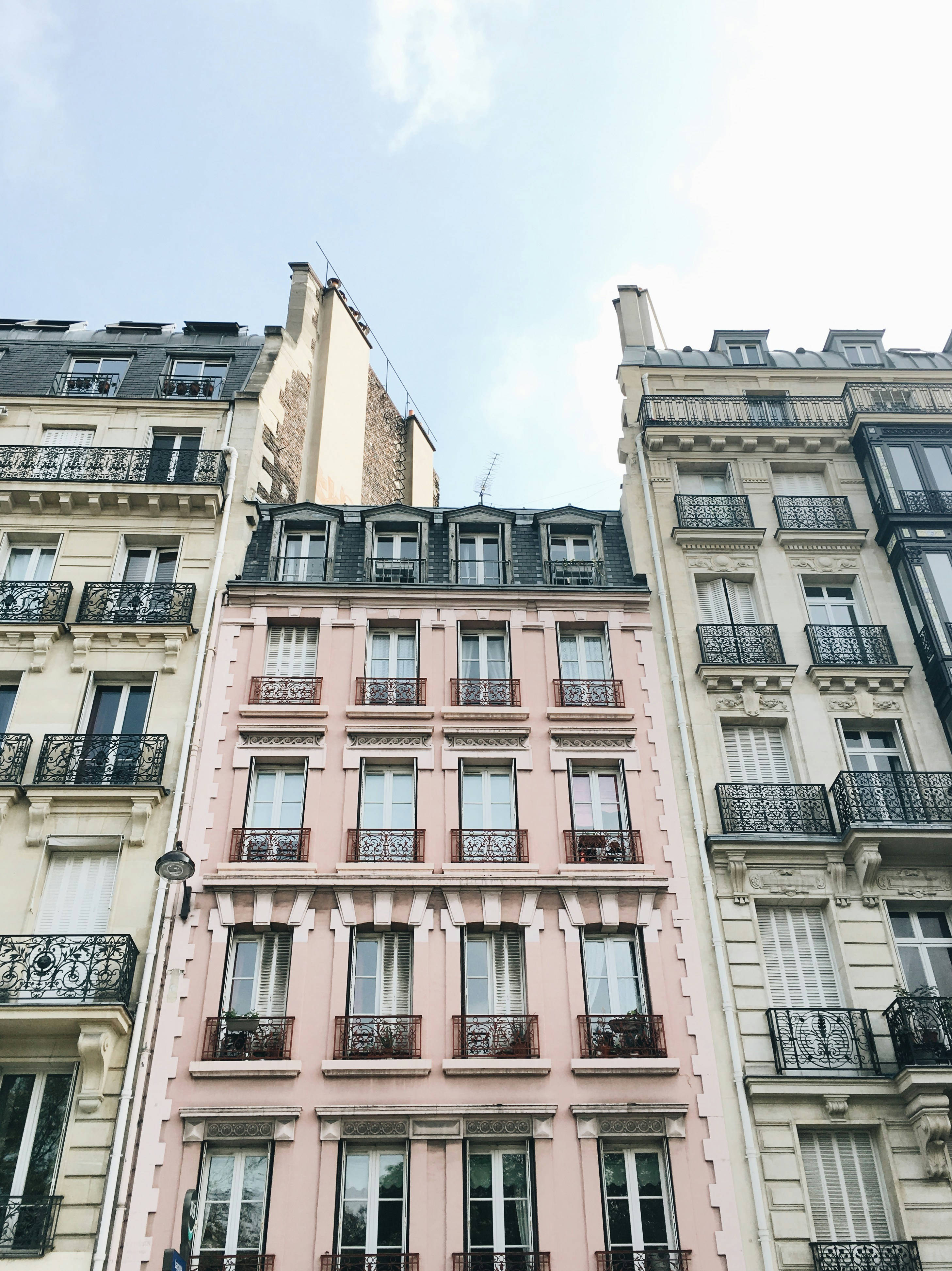 Elegant Parisian buildings showcasing intricate balconies and a harmonious color palette, with a soft sky backdrop.