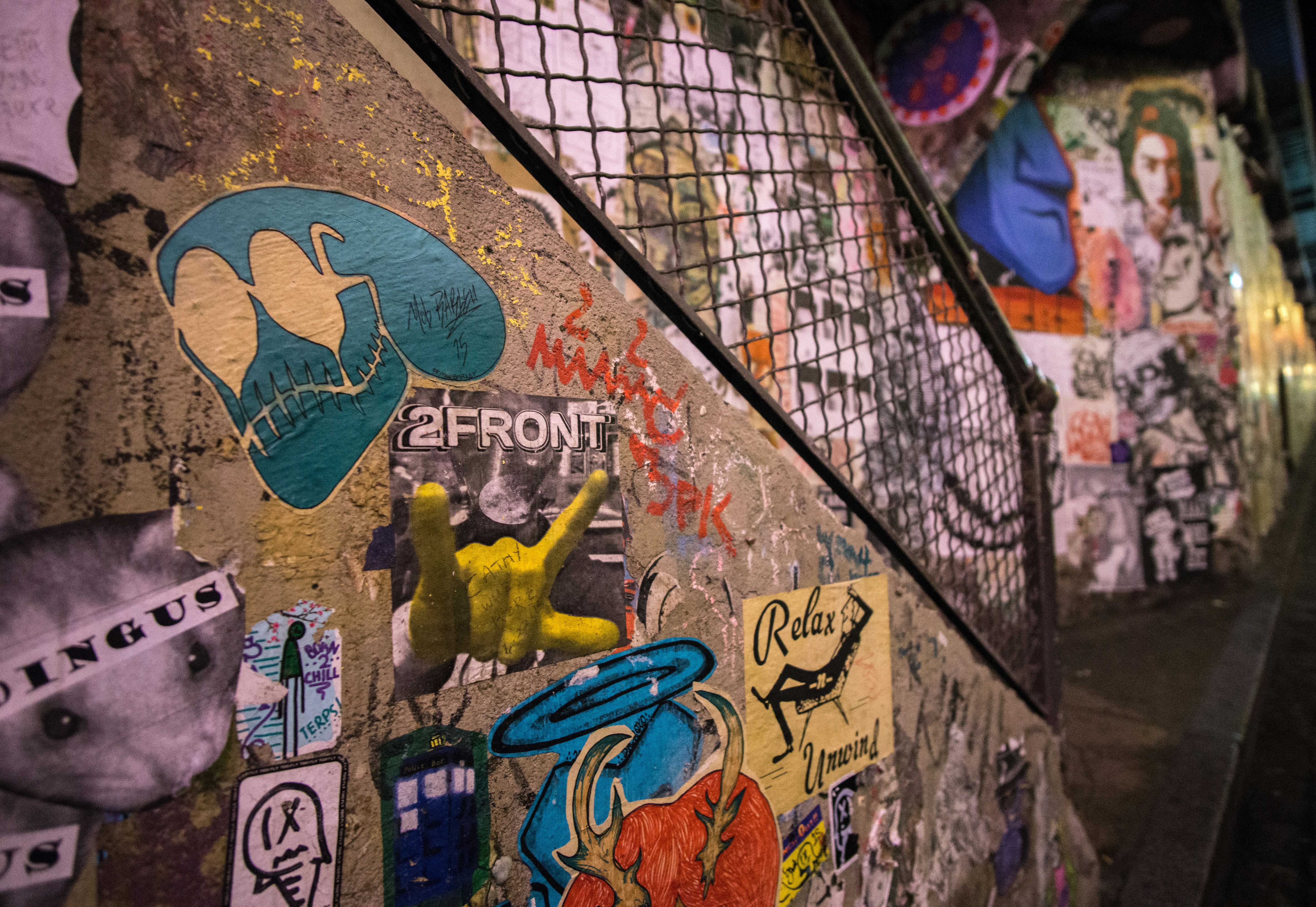 Vibrant street art and stickers adorn a textured wall, showcasing a blend of creativity and urban culture.