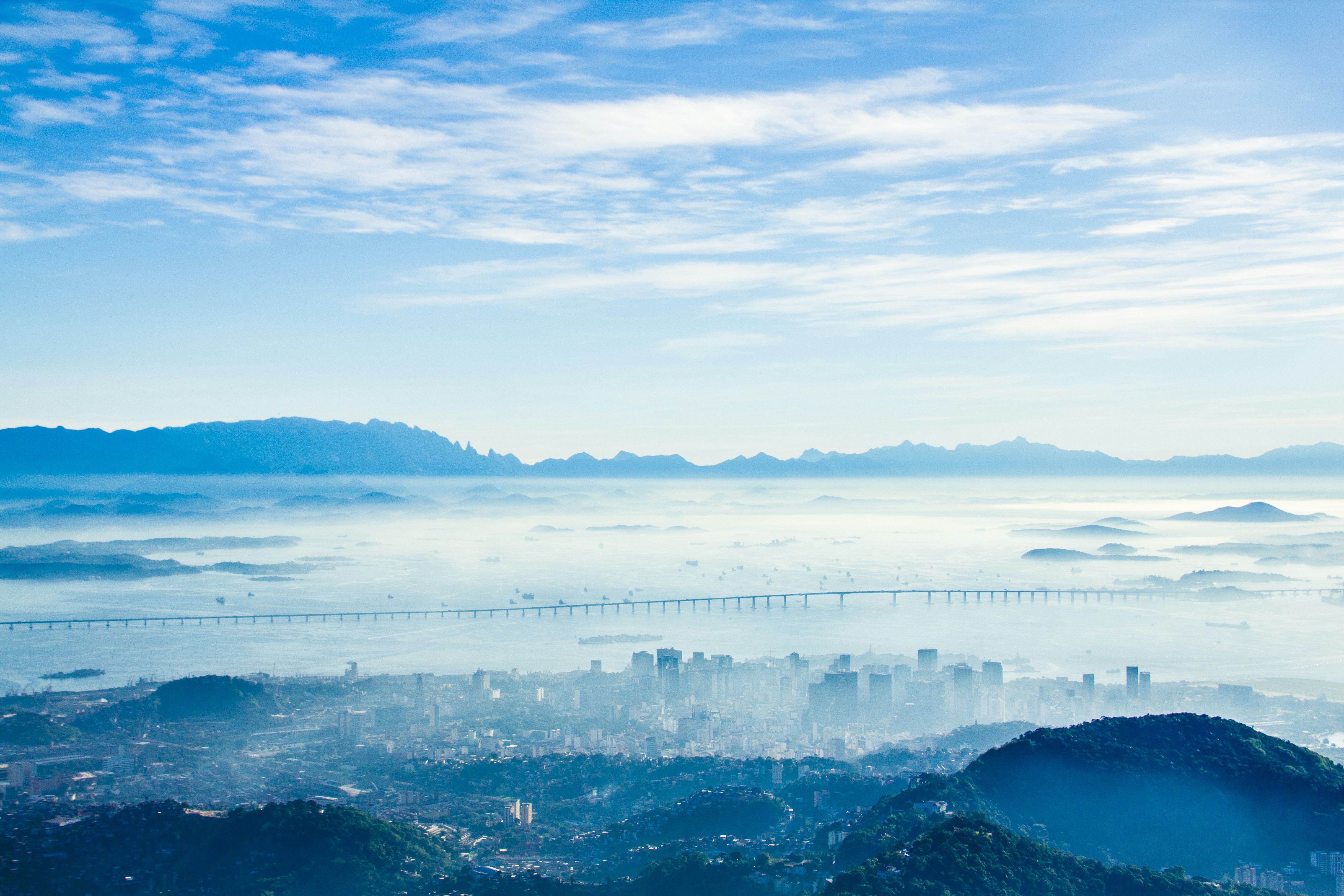 Distant city skyline enveloped in morning mist beneath a blue sky.