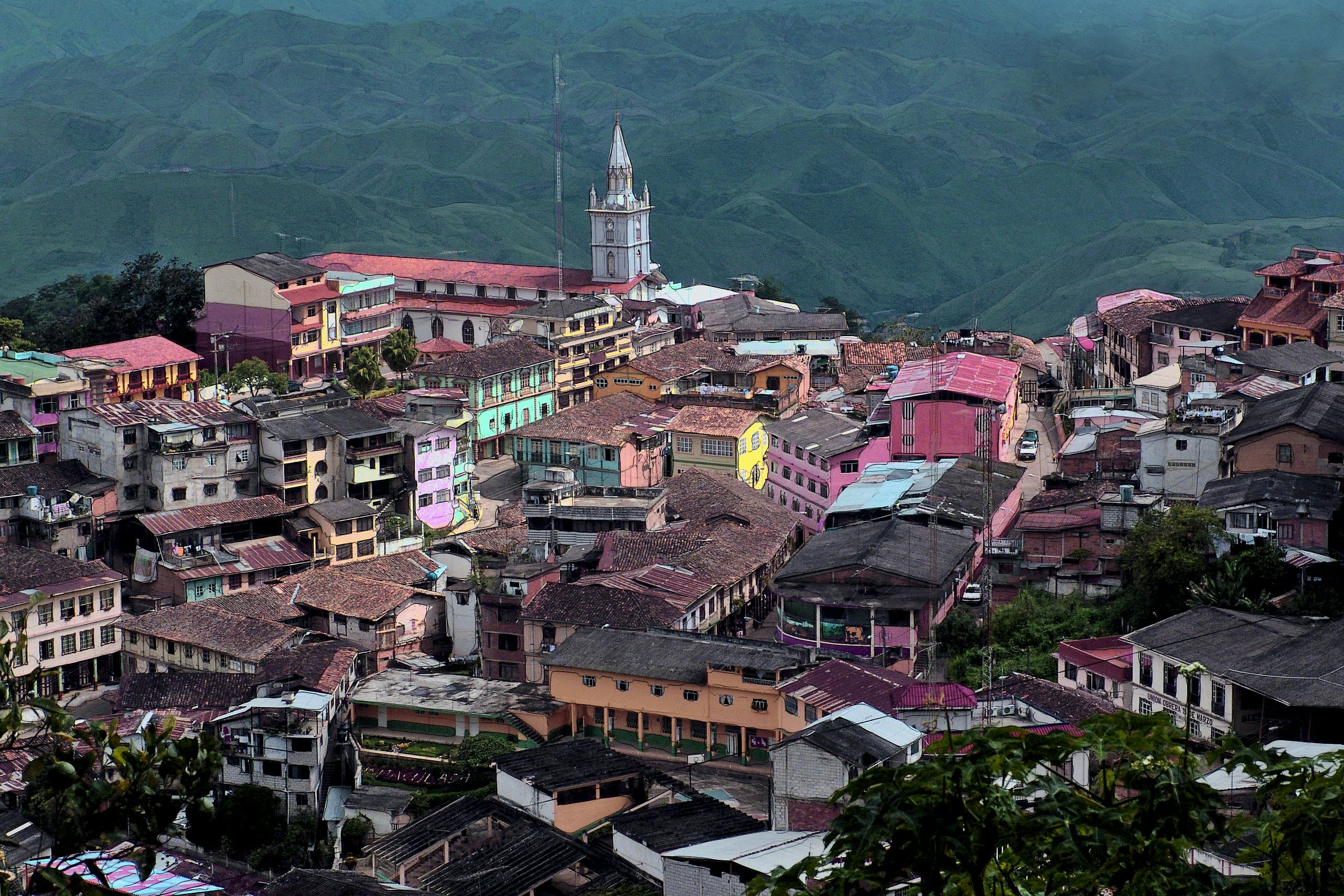 Vibrant hillside town with colorful buildings against a mountainous backdrop.
