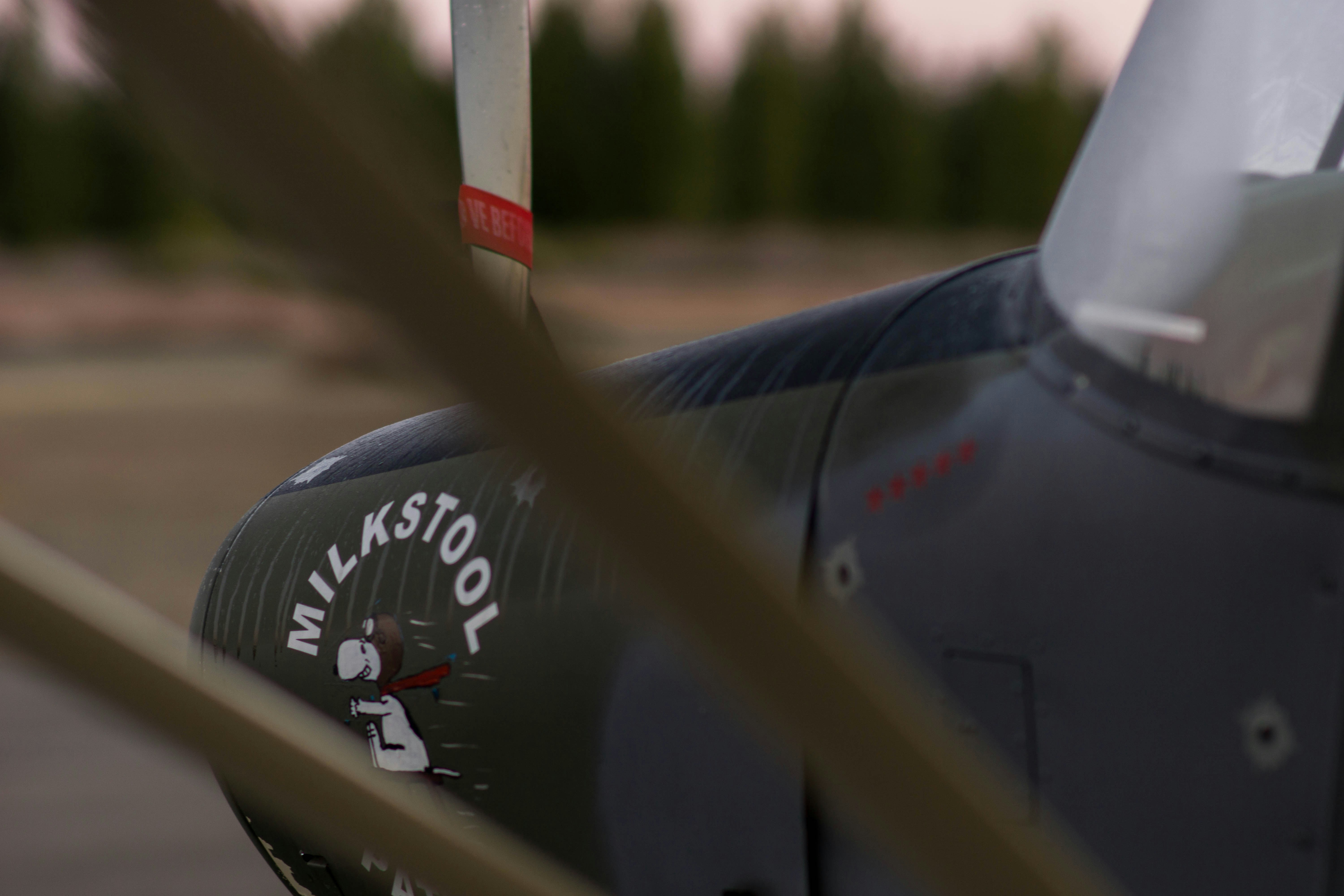 Close-up of a propeller featuring a playful 'Milkstool' logo, with blurred blades creating a sense of motion. The background hints at a serene landscape.