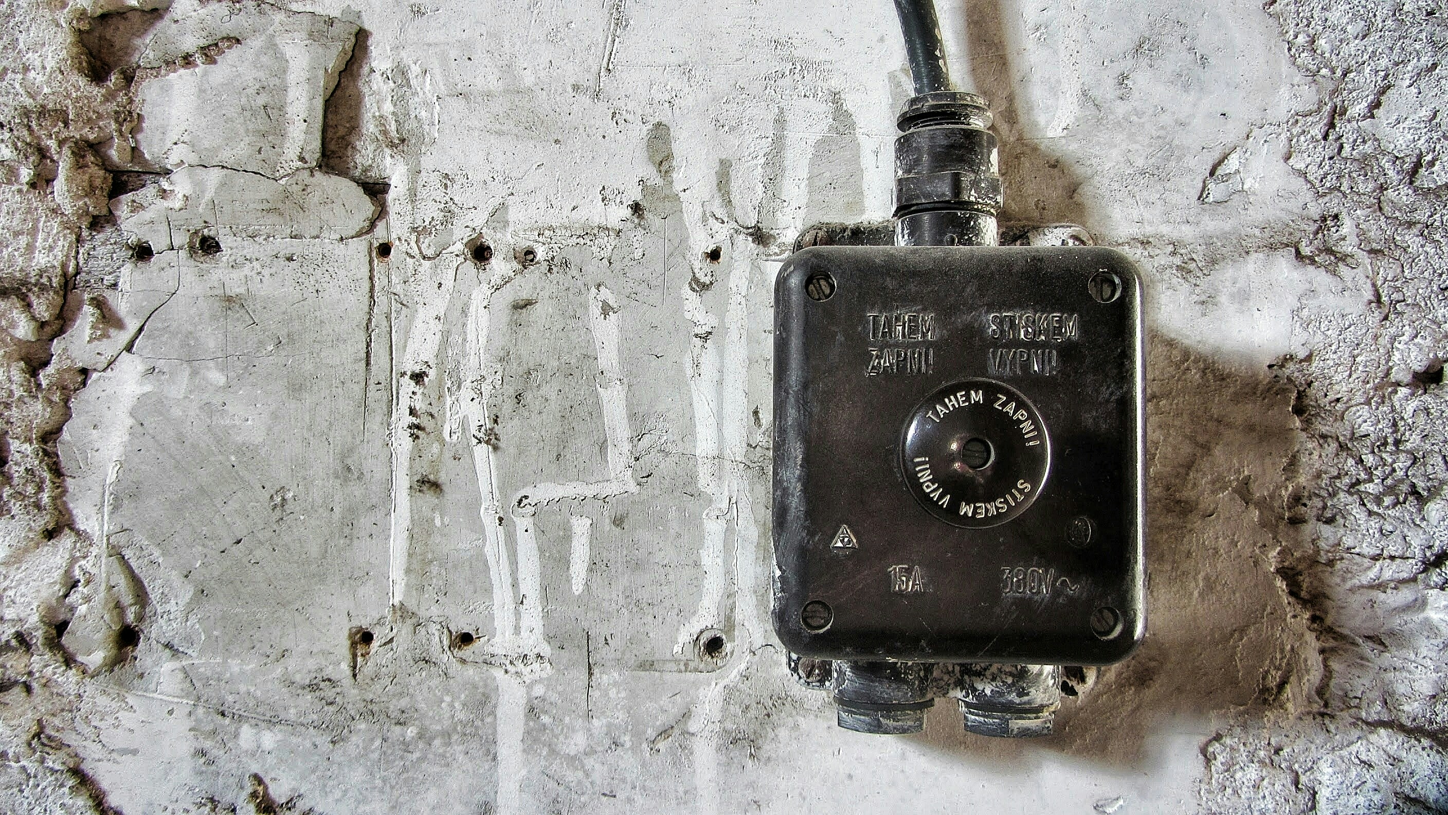Old electrical switch mounted on a weathered wall, showcasing signs of wear and neglect. The surrounding texture adds to the industrial aesthetic.
