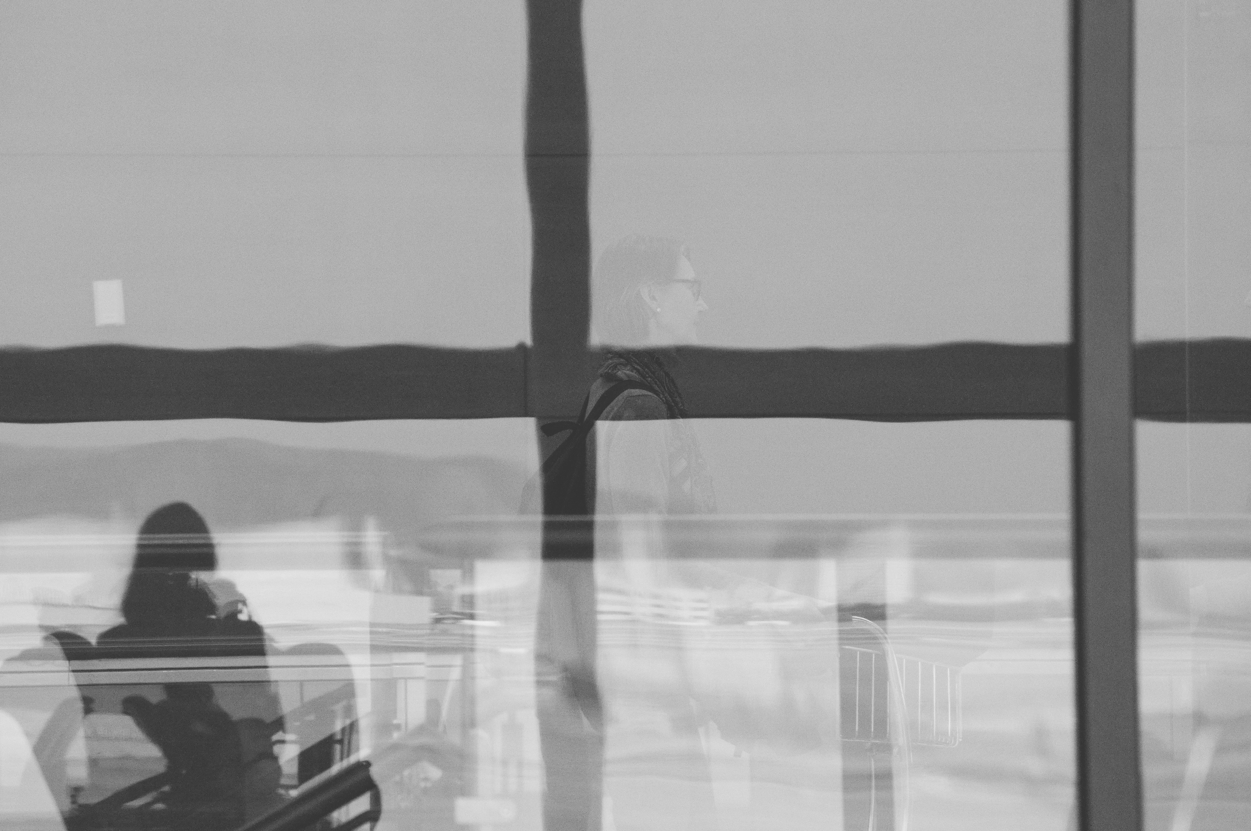 Silhouetted figures and reflections create a layered narrative against a minimalist backdrop. The interplay of light and shadow adds depth.