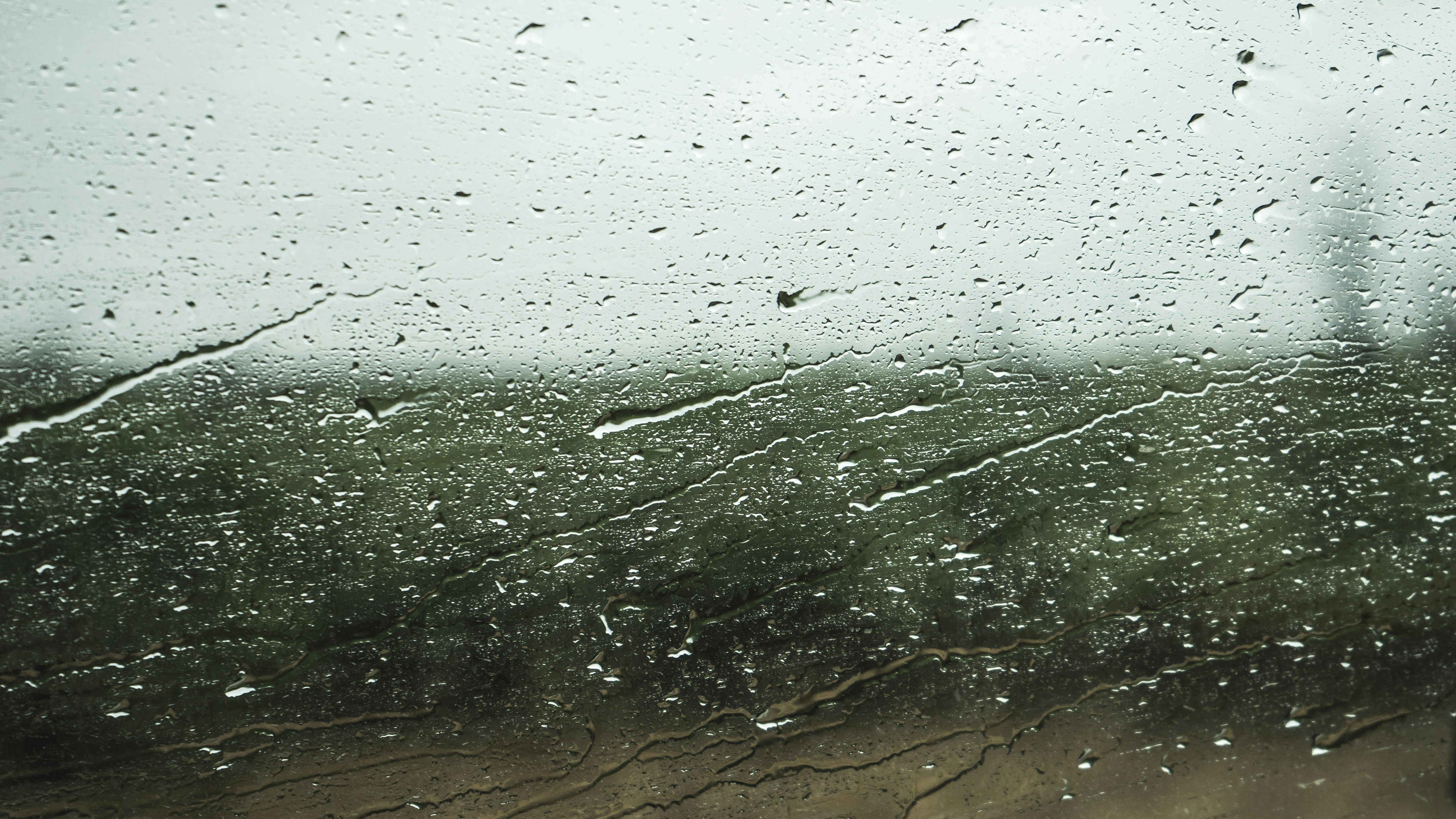 A view of a field through a rain covered window photo – Free Water ...