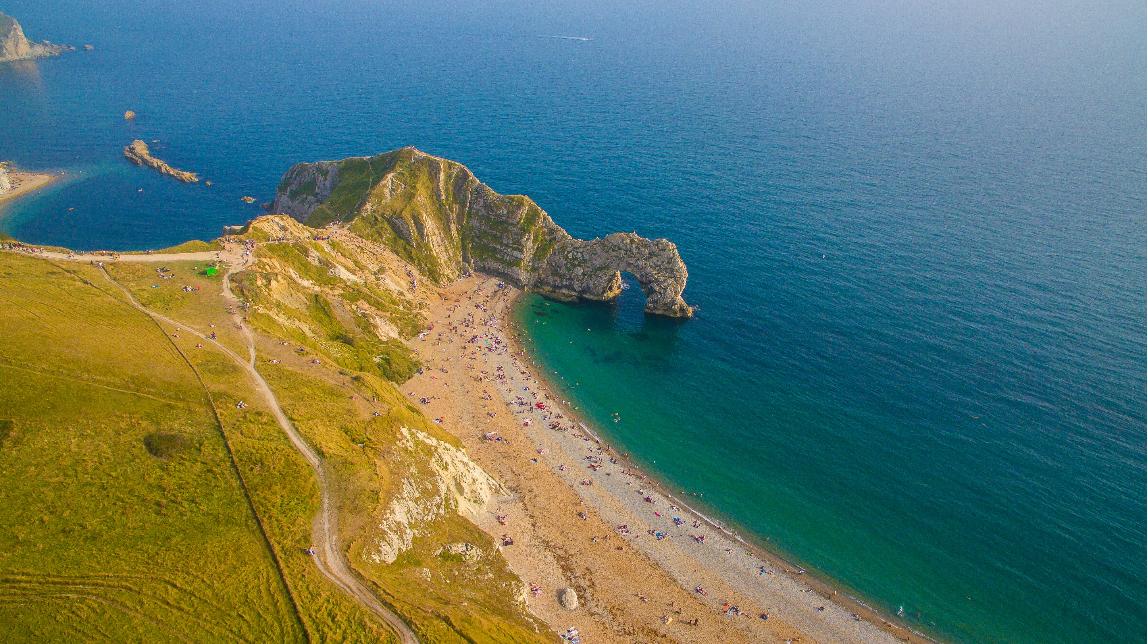 Aerial view of a rugged coastal landscape with a sandy beach meeting the clear blue sea.