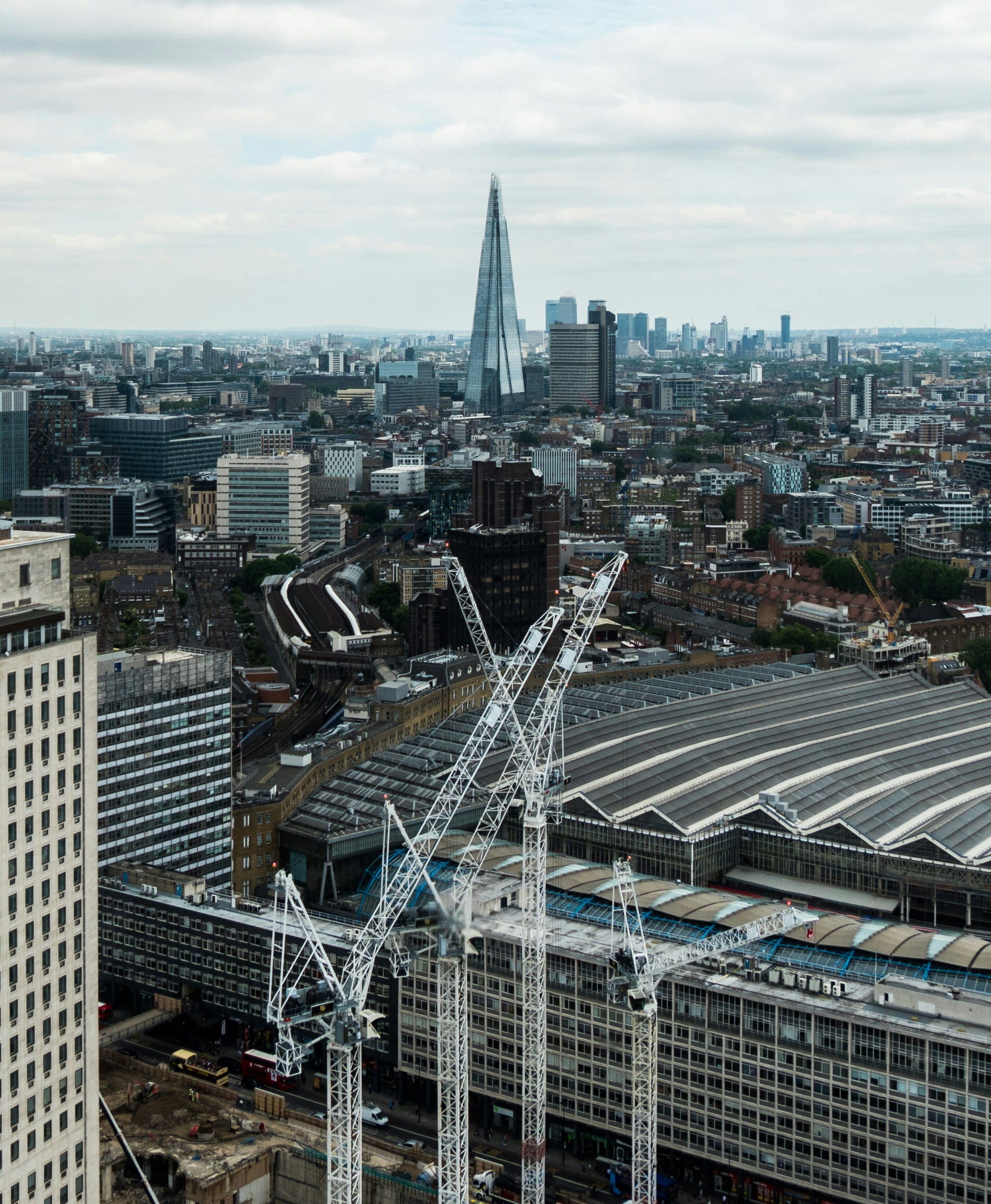 Construction cranes tower over a sprawling urban landscape, showcasing the dynamic growth of the city with modern skyscrapers in the backdrop.