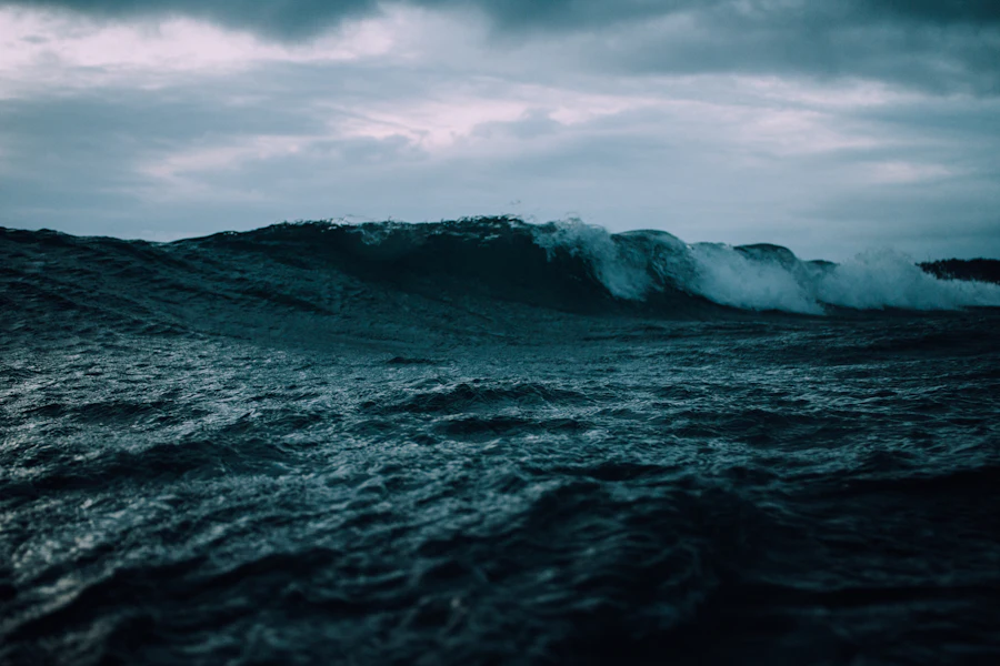 Dark waves crashing under a turbulent, cloud-filled sky.