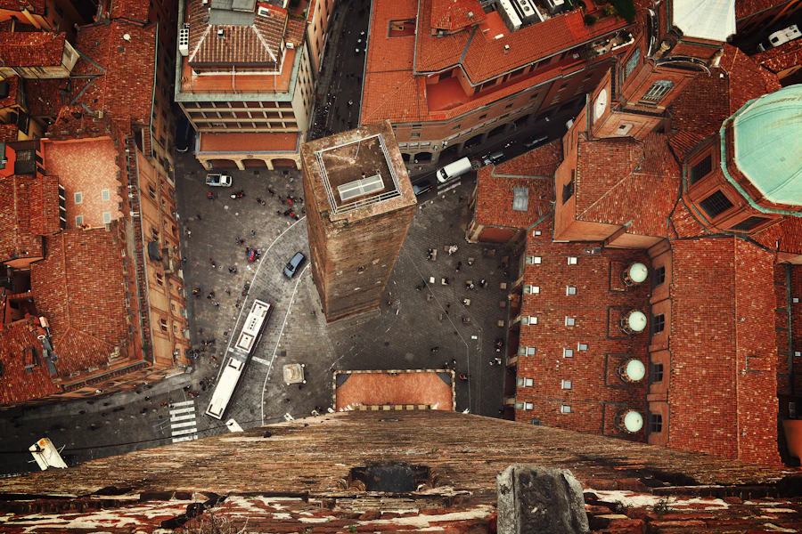 Aerial view of Bologna's red rooftops and bustling streets from a high vantage point.