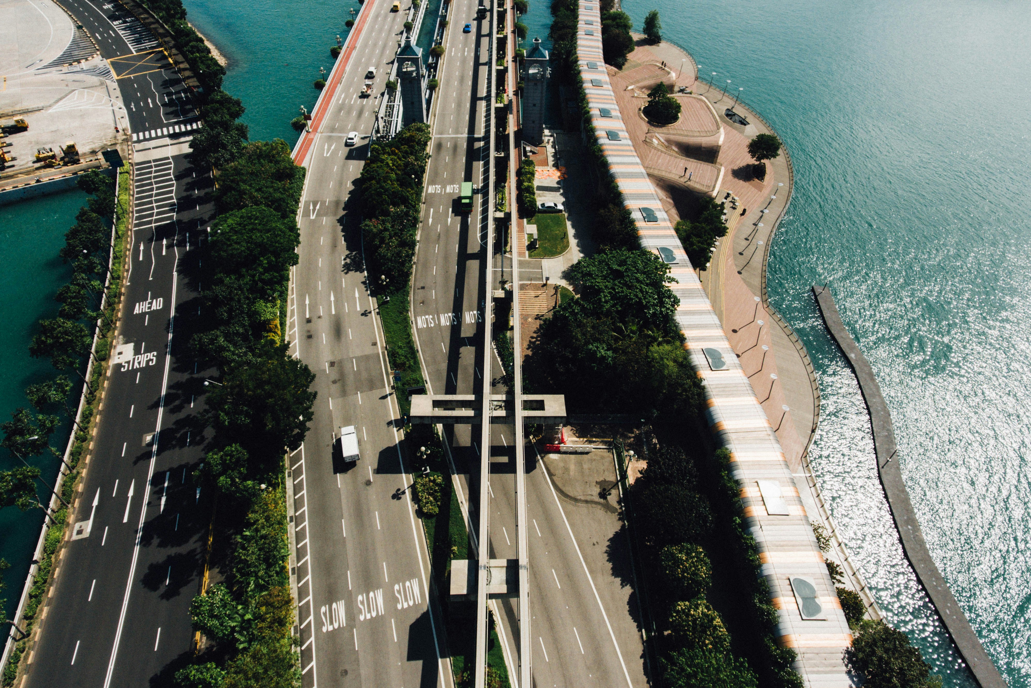 Aerial view of intersecting highways and a railway alongside a shimmering blue river.