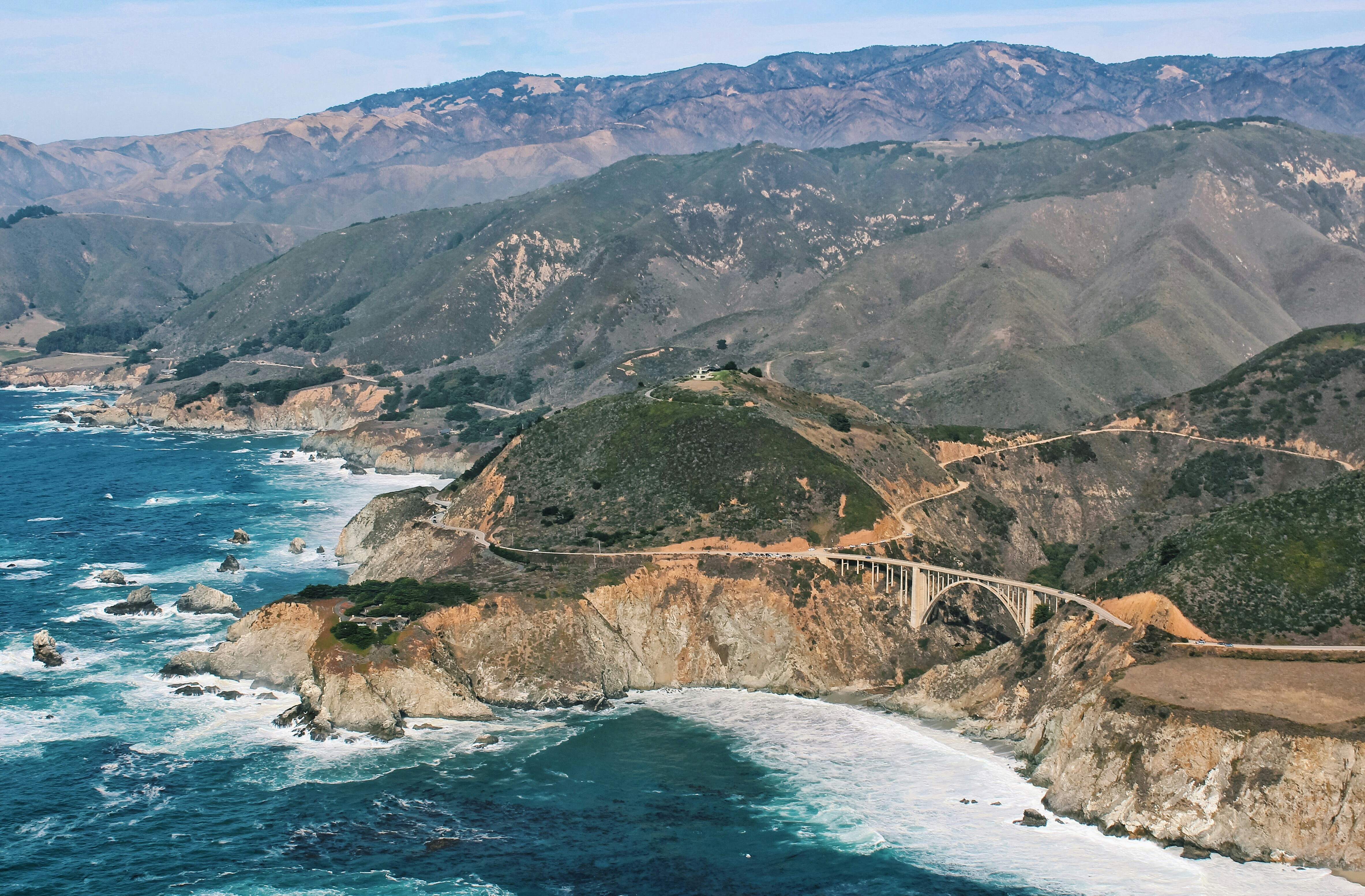 Scenic view of a coastal landscape with a winding road and dramatic cliffs.