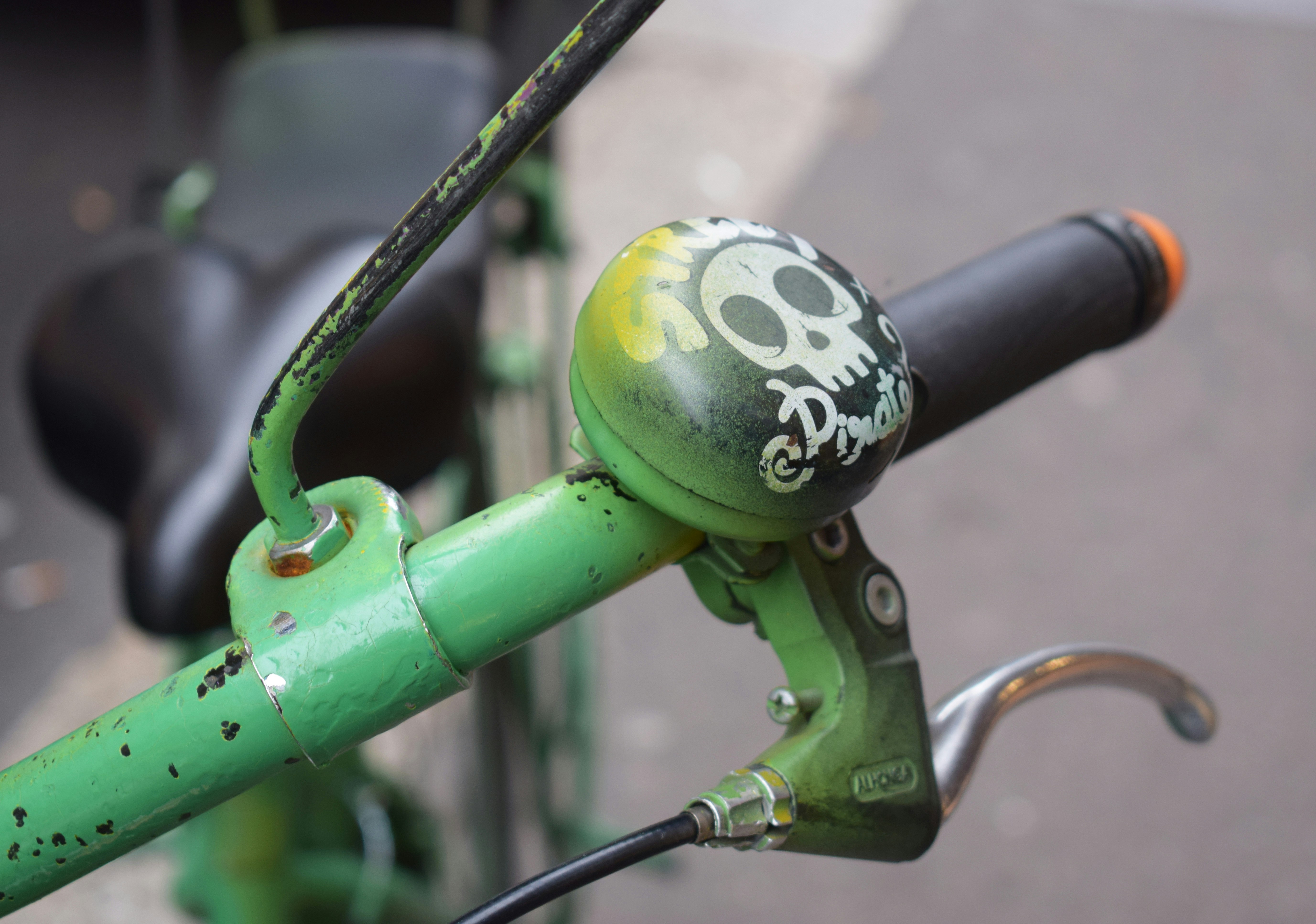 Close-up of a vintage bicycle handlebar with a distinctive skull bell, showcasing its weathered paint and character. 