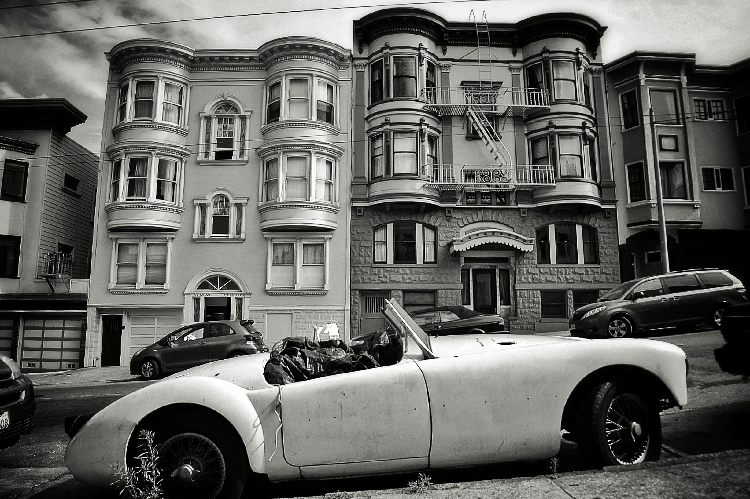 Chrome and Charm: A Vintage Convertible Beside Bay-Windowed Facades