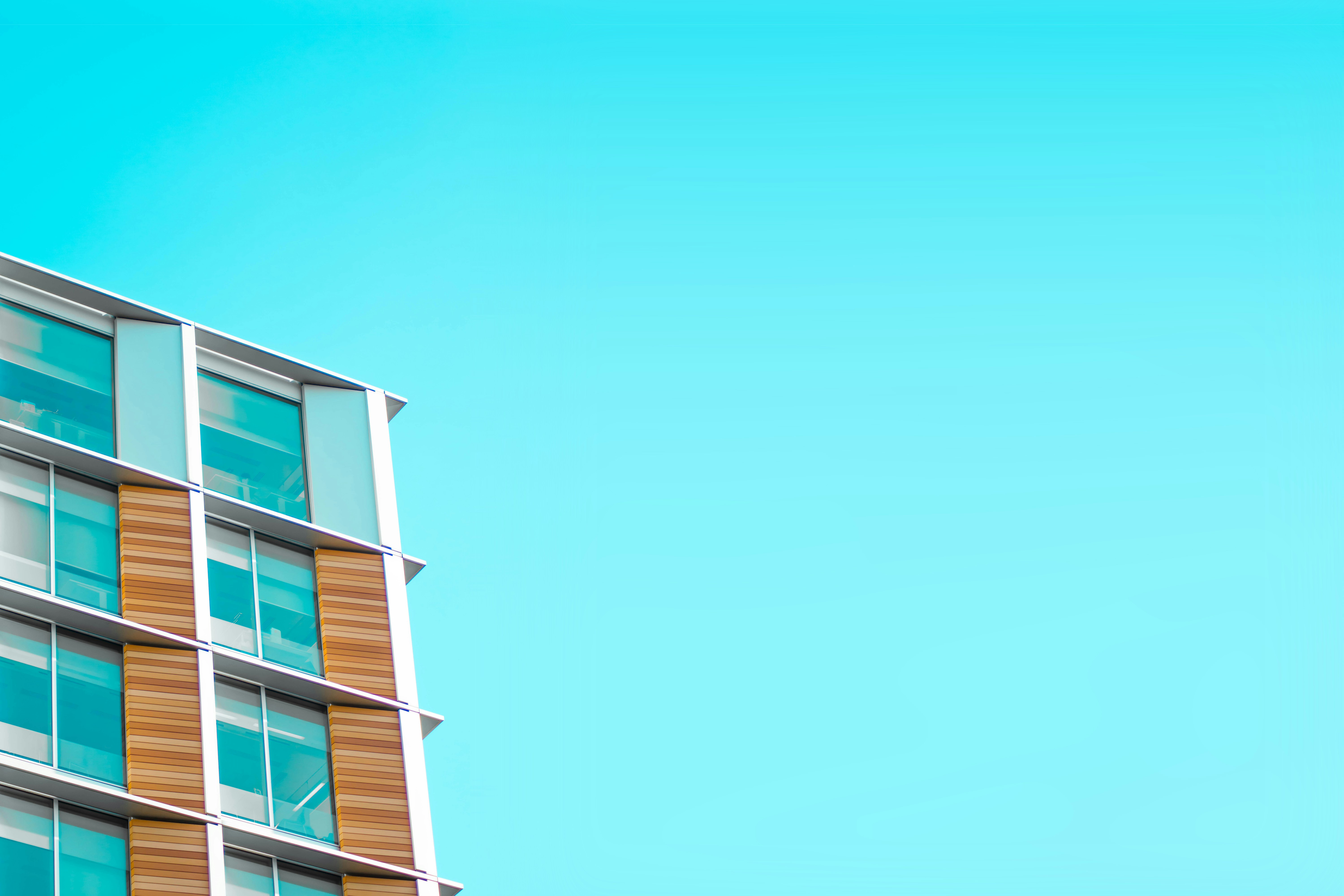 Contemporary building corner showcasing a blend of glass and wooden panels under a clear blue sky.