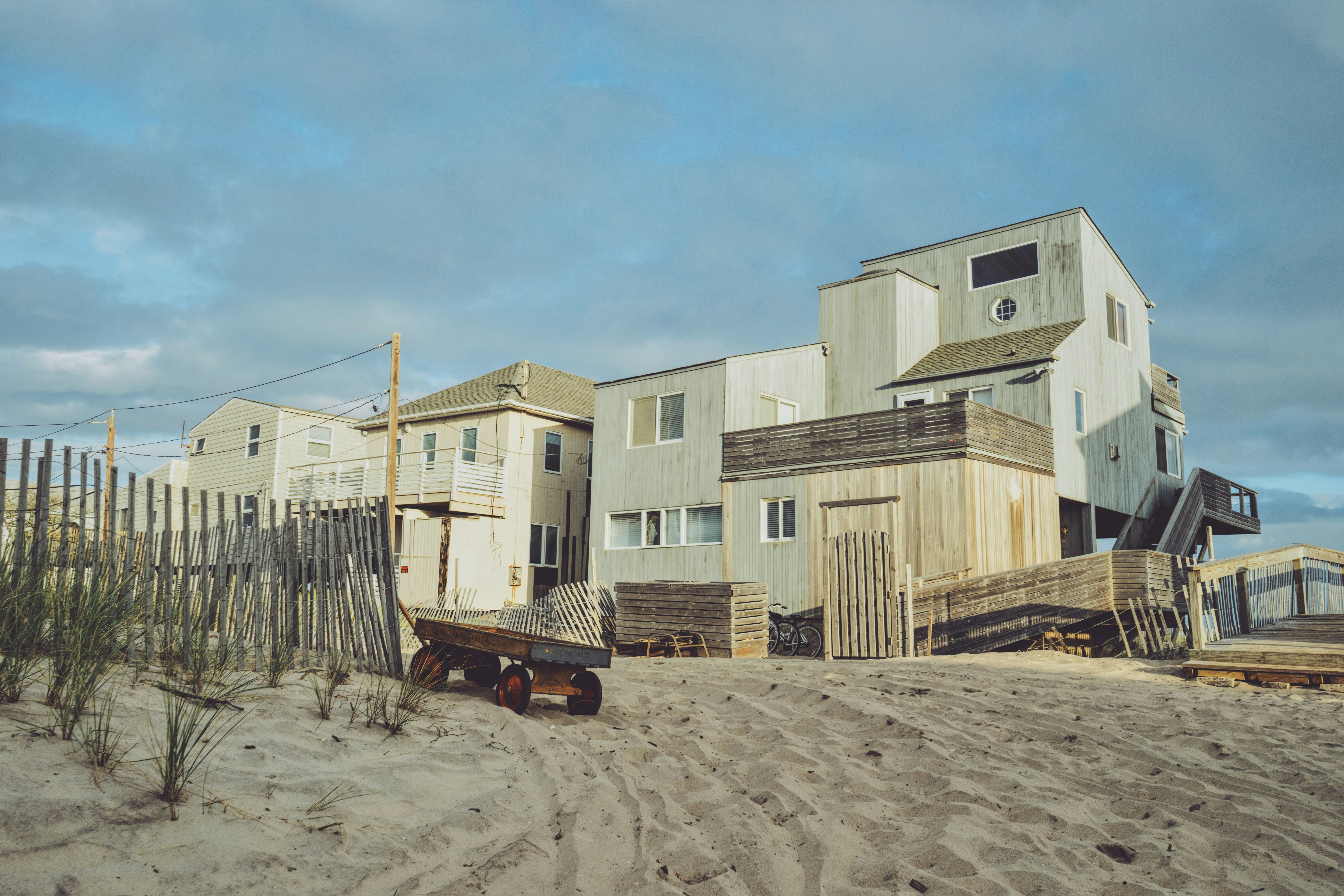 Beachfront houses with unique angular architecture set against a cloudy sky.