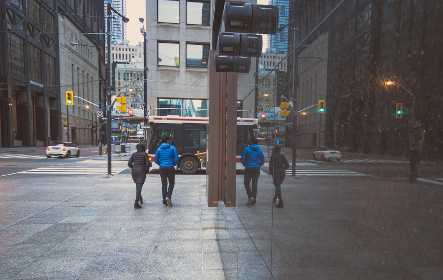 Four pedestrians walk across a downtown intersection with a bus waiting ahead and tall buildings framing the street. Reflections in the glass create a layered urban scene.